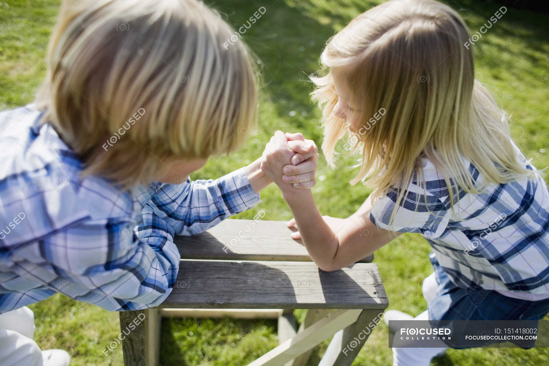 High Angle View Of Siblings Arm Wrestling On Wooden Table In Back Yard — Playing Sister Stock