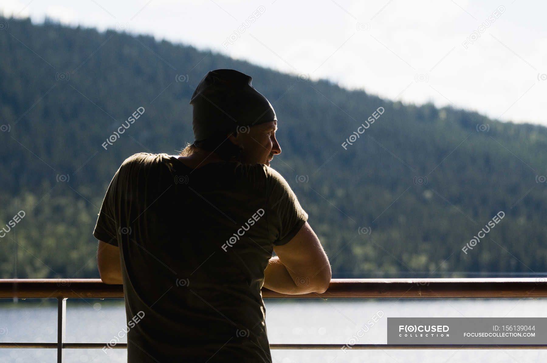 Man leaning on railing — rear view, trees - Stock Photo | #156139044