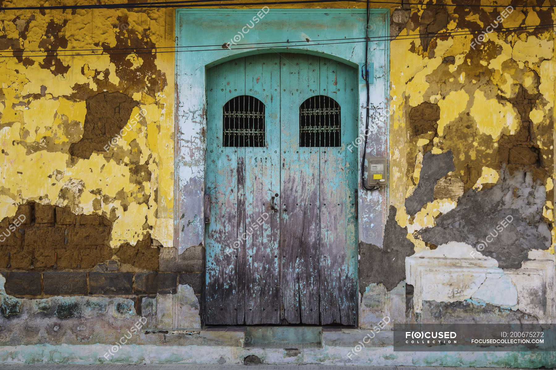 Worn and weathered facade of a building with peeling paint and double doors; Nicaragua — outdoor ...