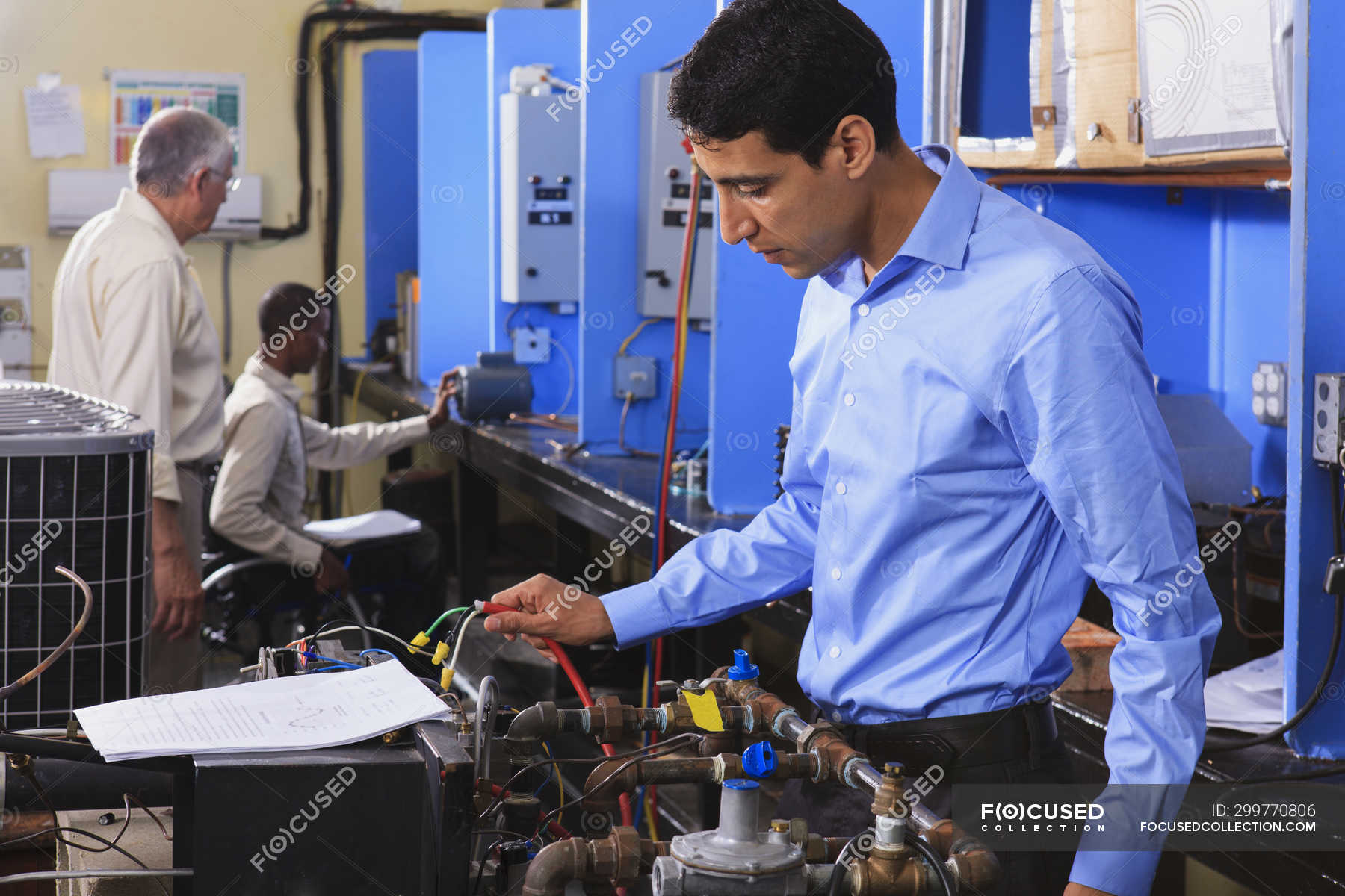 Student examining control system wiring on furnace in HVAC classroom ...