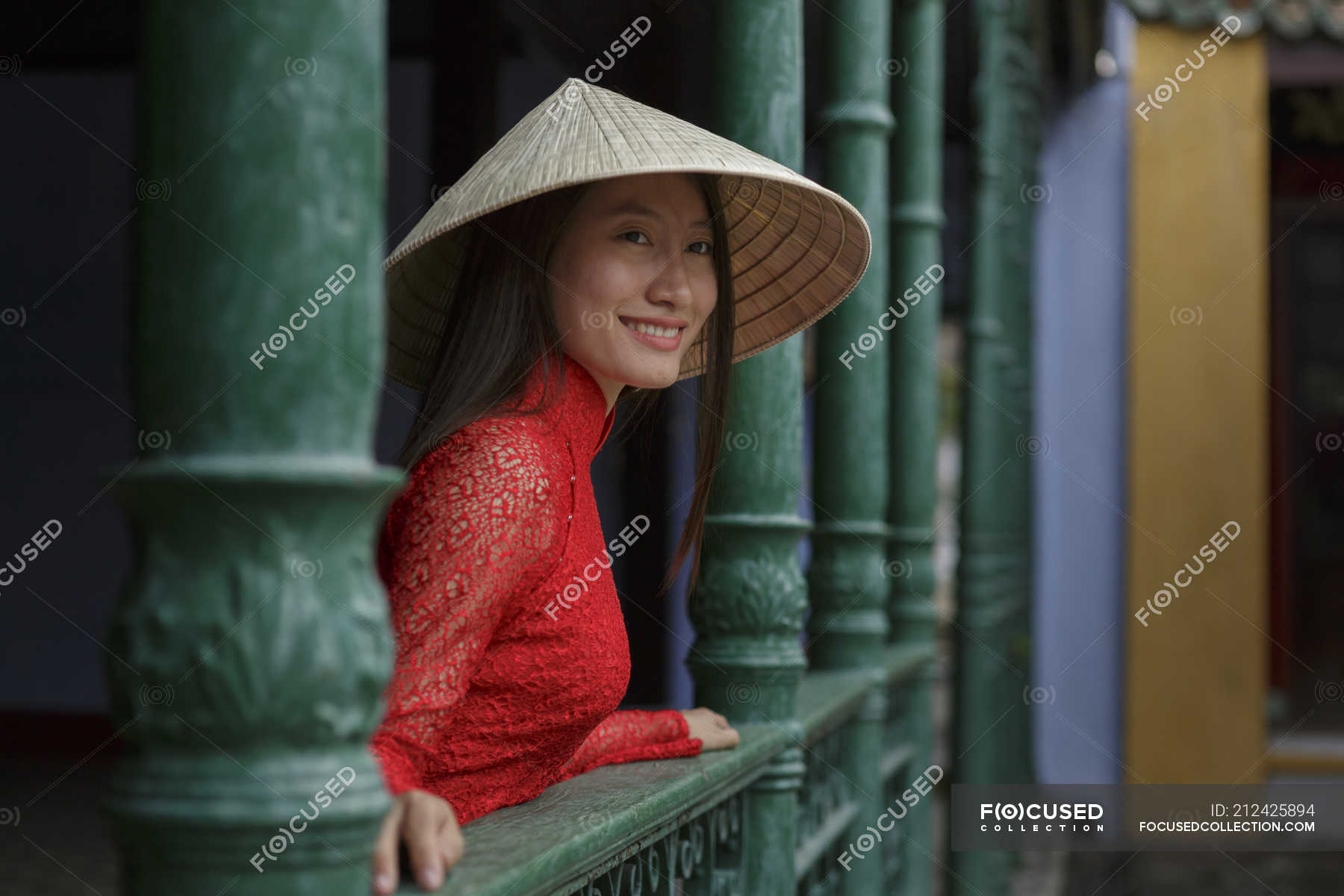 Vietnamese woman wearing conical hat standing on a balcony in Hoi An in her Ao Dai — people ...