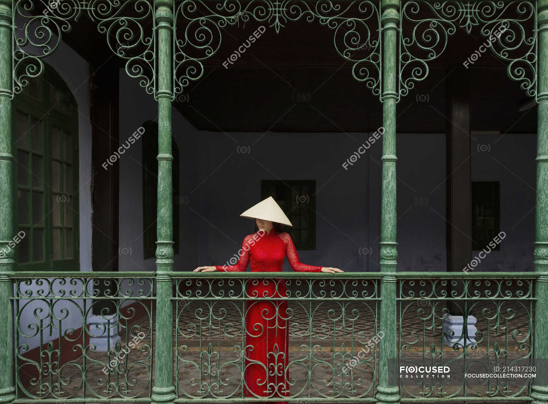 Vietnamese woman wearing conical hat standing on a balcony in Hoi An in her Ao Dai — old town ...