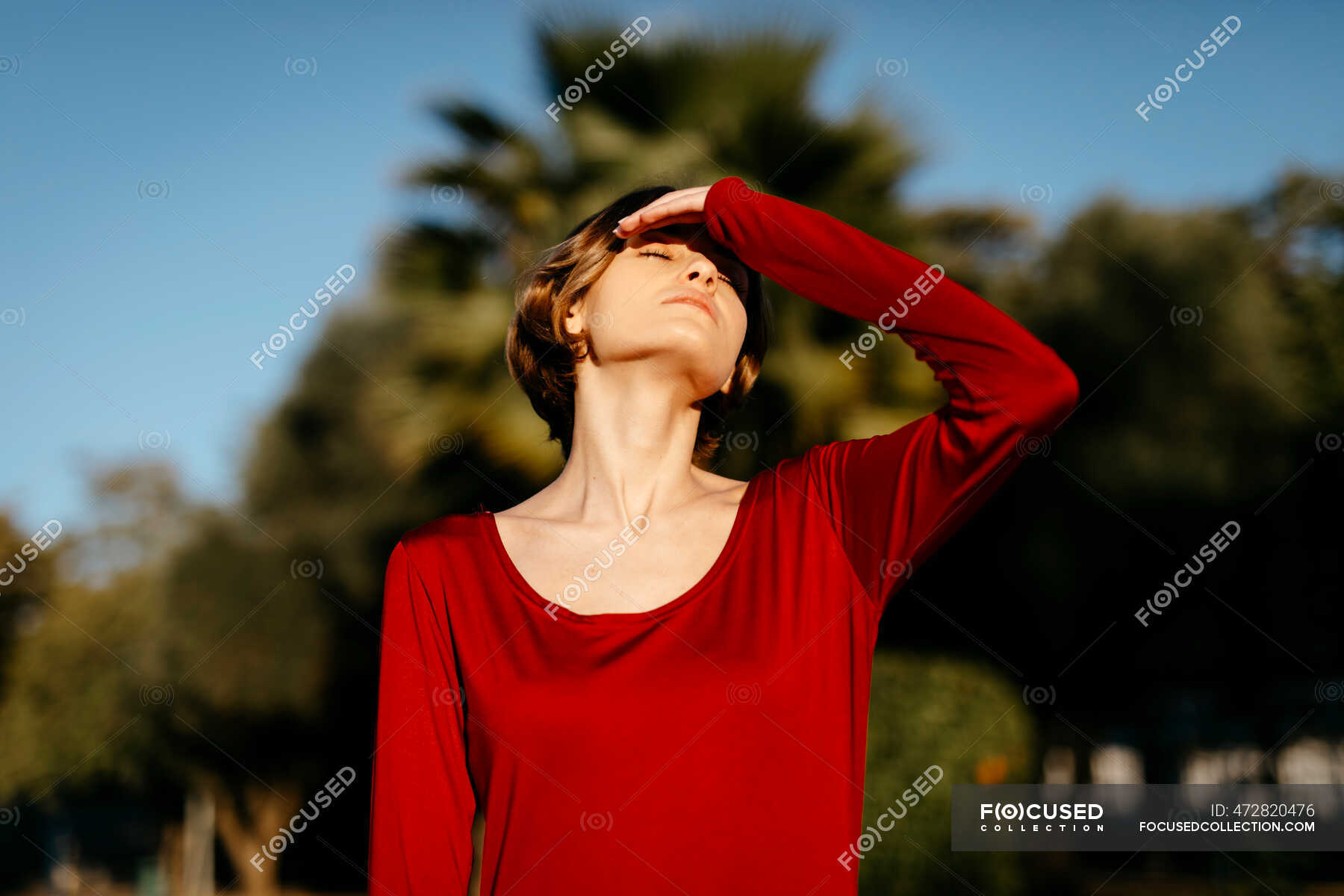 Portrait Of Young Woman With Closed Eyes Wearing Red Dress In A Park