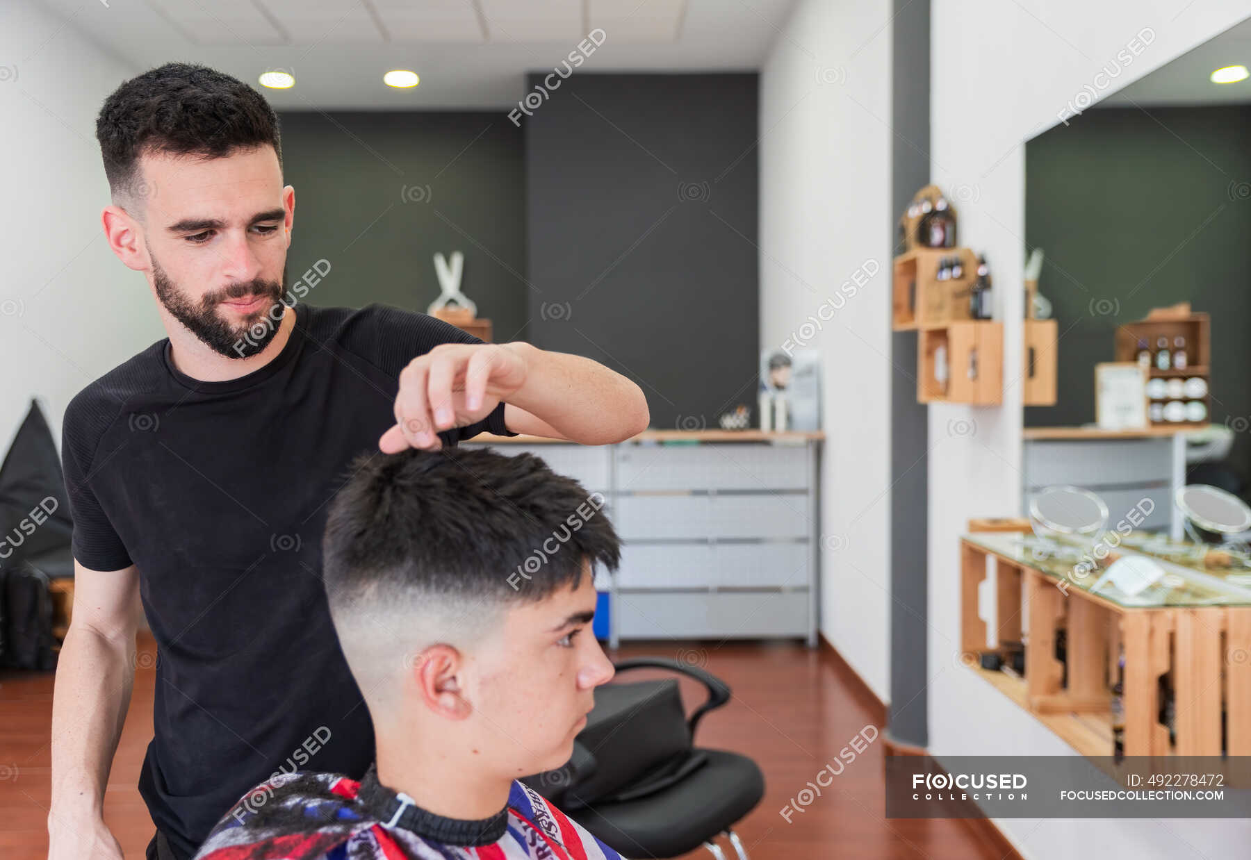 Male barber combing hair of customer while doing hairstyle at salon ... Male barber combing hair of customer while doing hairstyle at salon ...