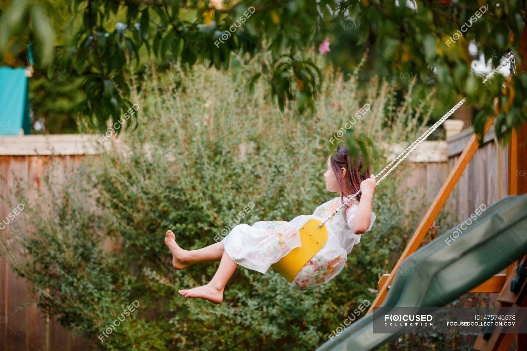 A Happy Barefoot Girl Swings On A Playlet Under A Tree In Summer — Copy Space Together Stock