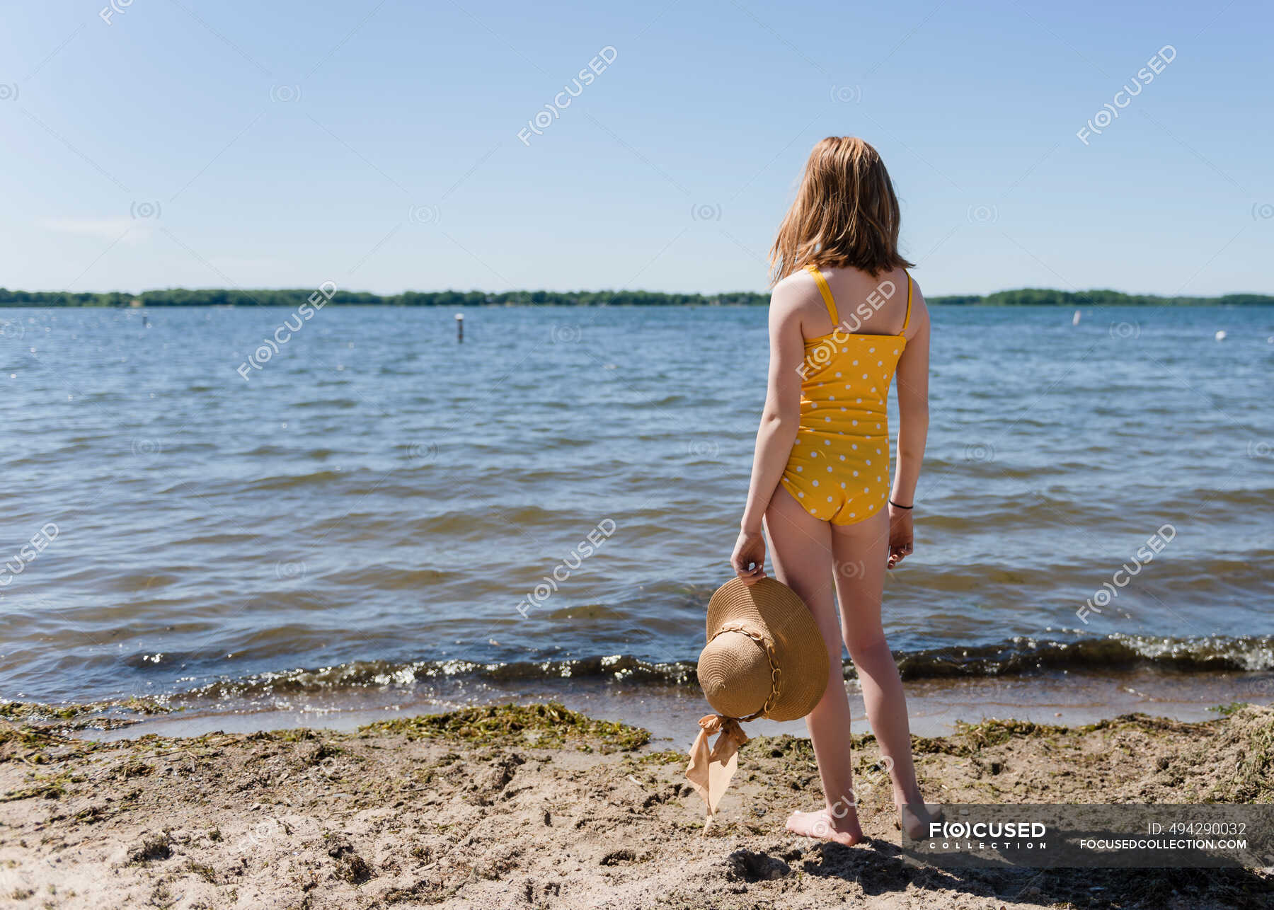 Tween Girl In A Yellow Swimsuit With Sunhat By Lake Shore — Polka