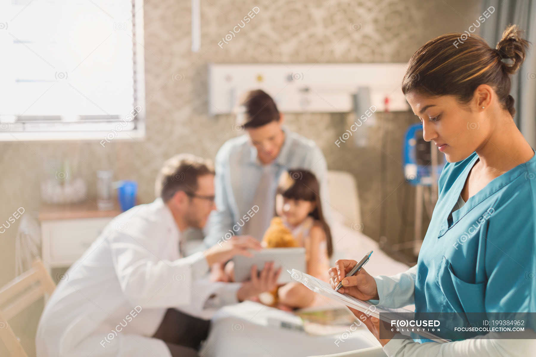 Female Nurse Taking Notes On Medical Record Clipboard While Doctor