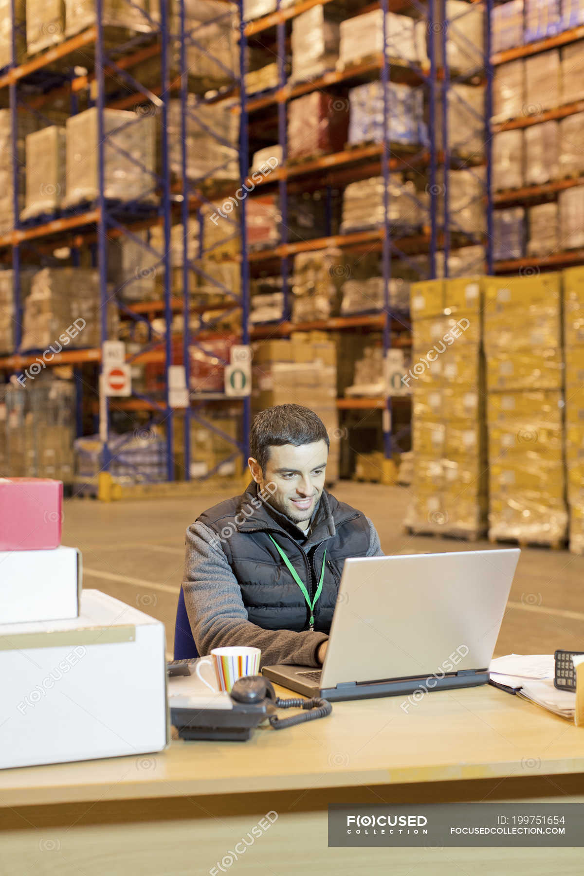 Worker using laptop in warehouse — Focus On Foreground, Protective ...