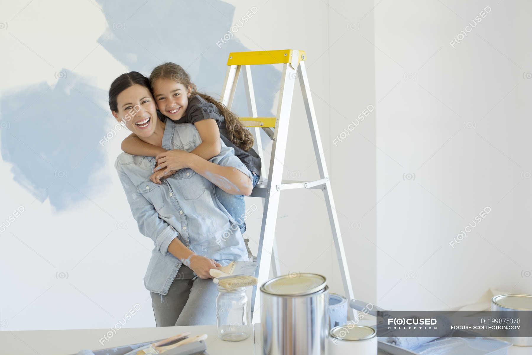 Portrait of mother and daughter hugging near paint supplies — Brazilian ethnicity, Self ...