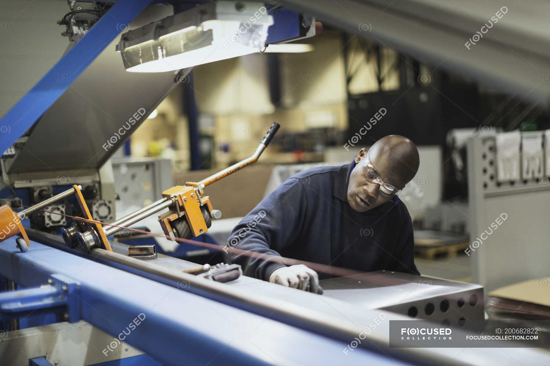 Worker operating machinery in steel factory — head and shoulders ...