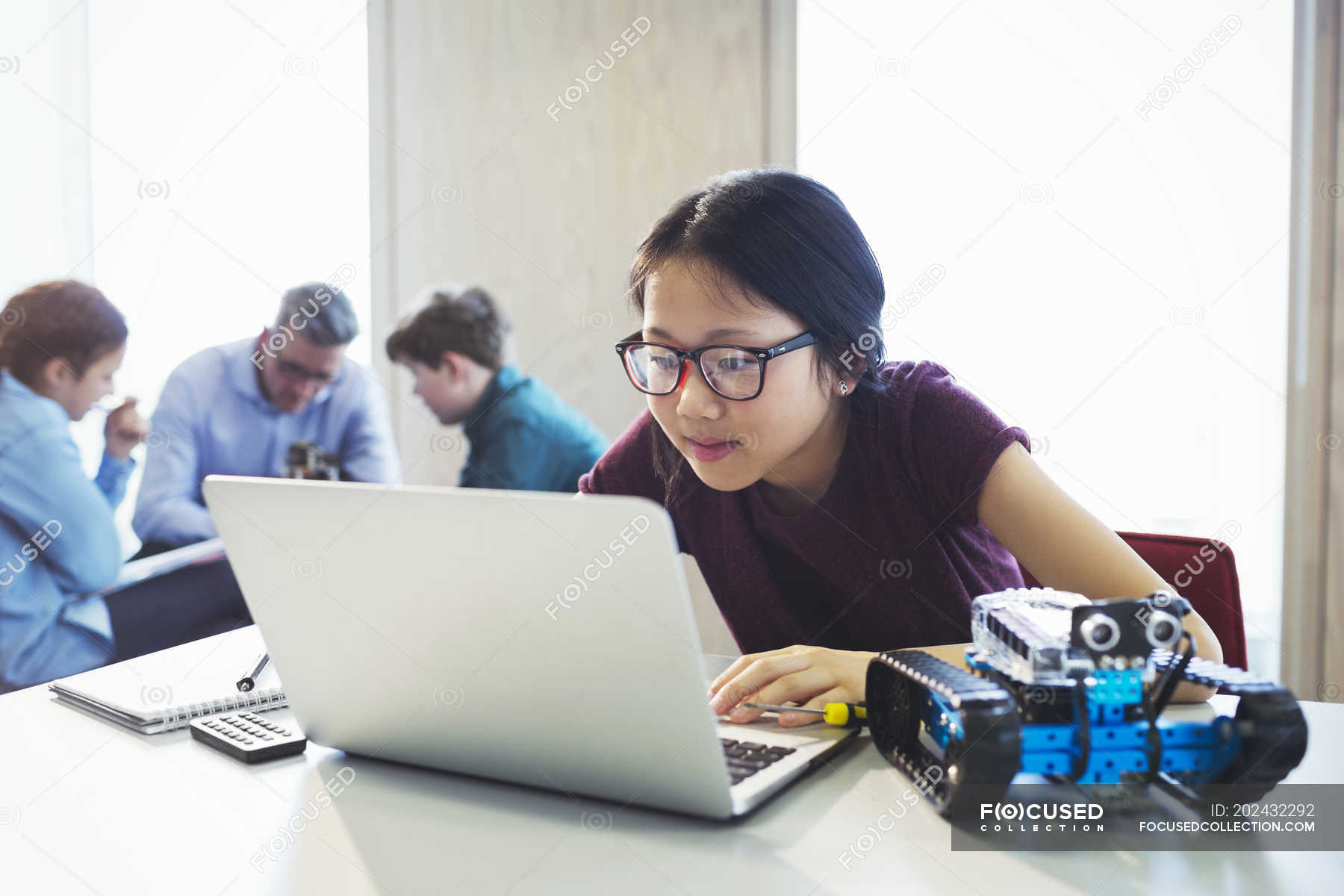 Focused girl student programming robotics at laptop in classroom ...