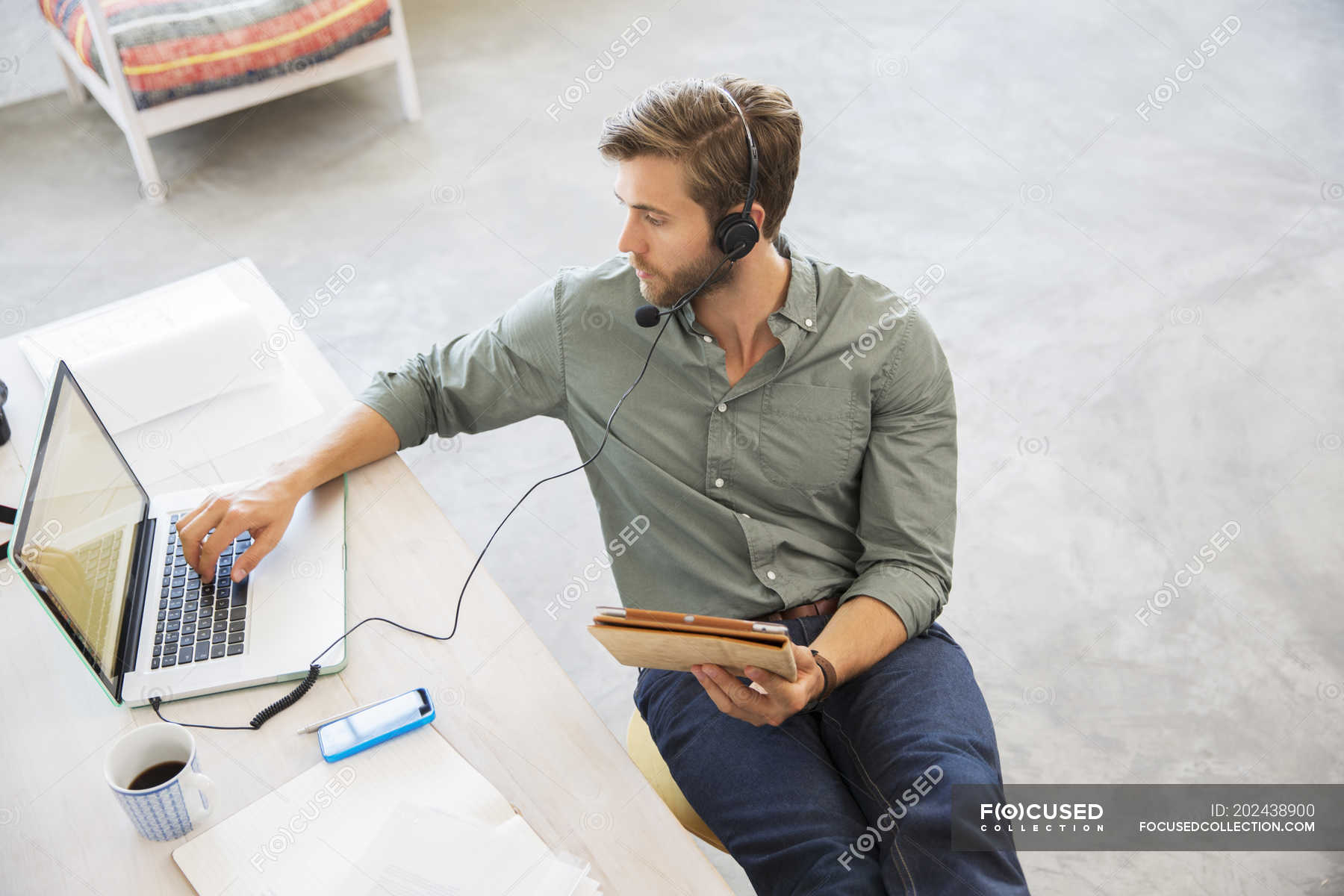 Young man sitting at desk working with laptop — working from home, male ...