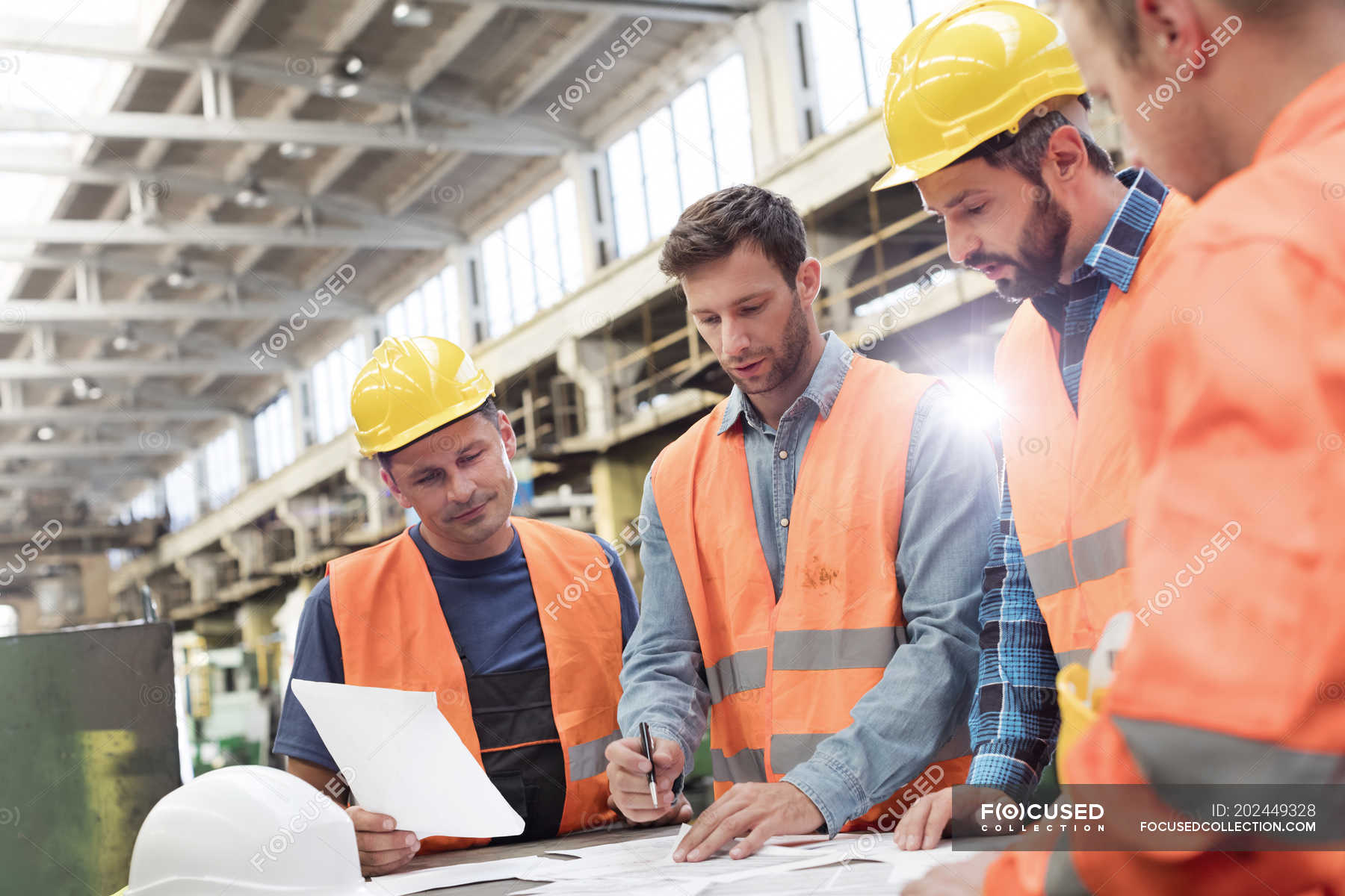 Trabalhadores e engenheiros de aço que reúnem revisão de plantas na ... Trabalhadores e engenheiros de aço que reúnem revisão de plantas na ...