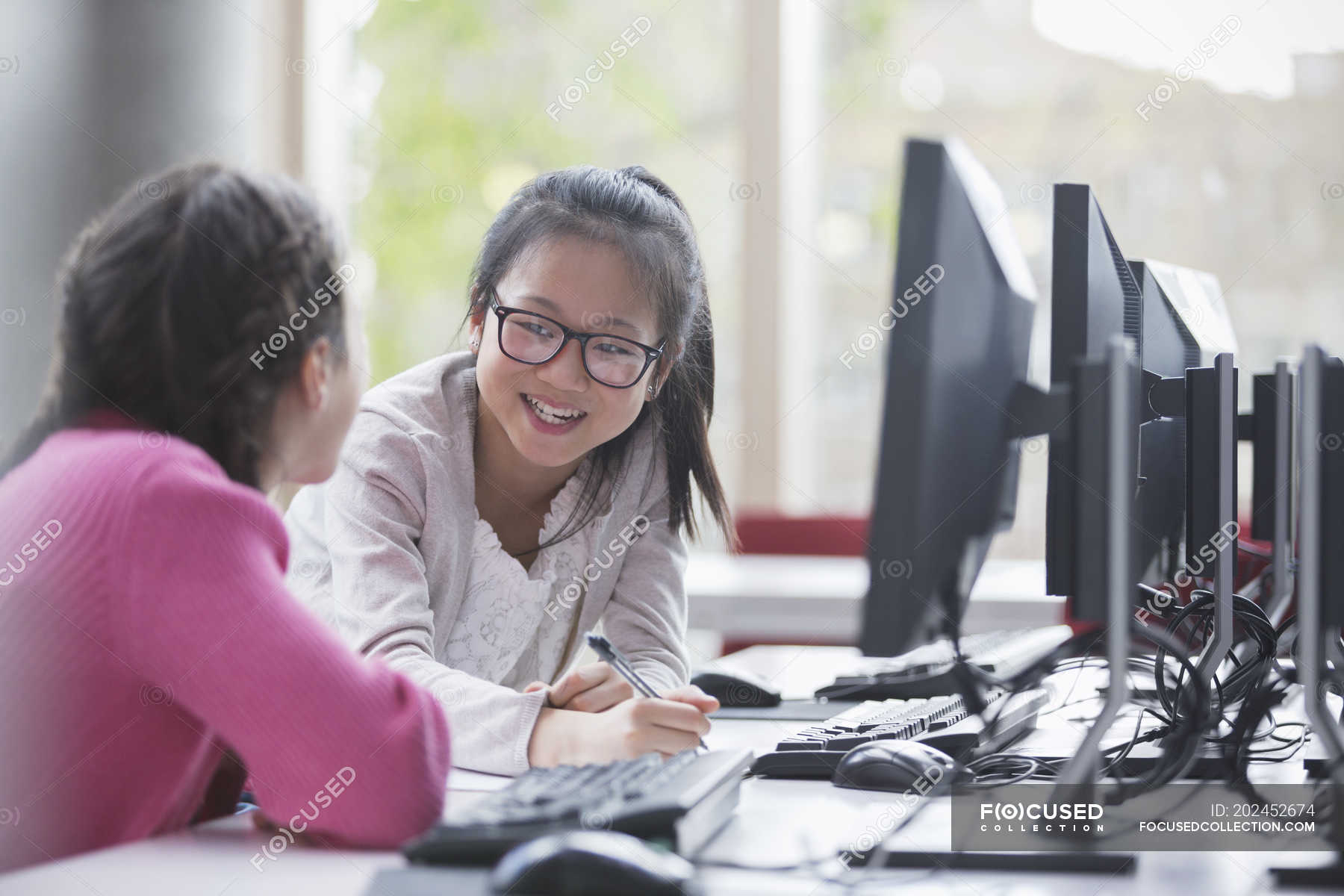 Smiling girl students researching at computer in laboratory classroom ...