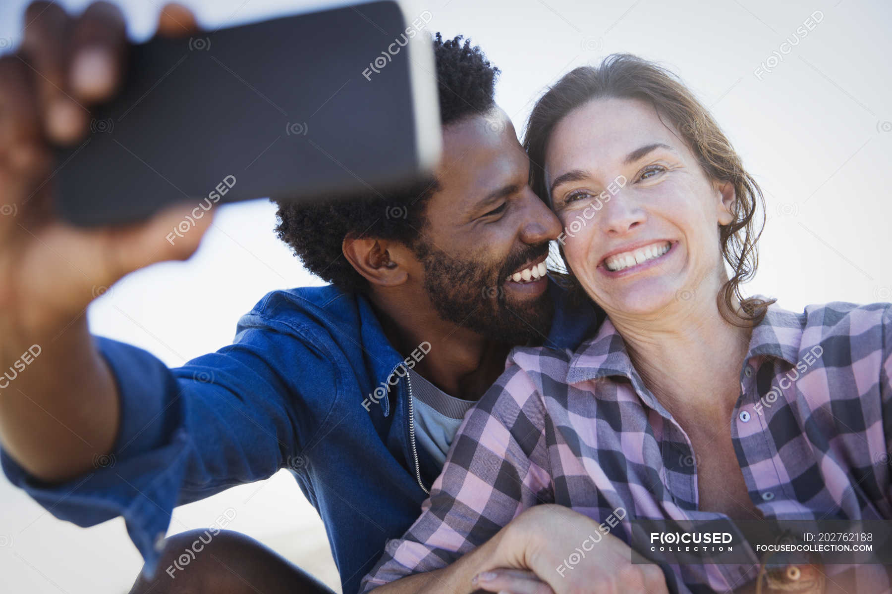 Smiling Enthusiastic Multi Ethnic Couple Taking Selfie With Camera