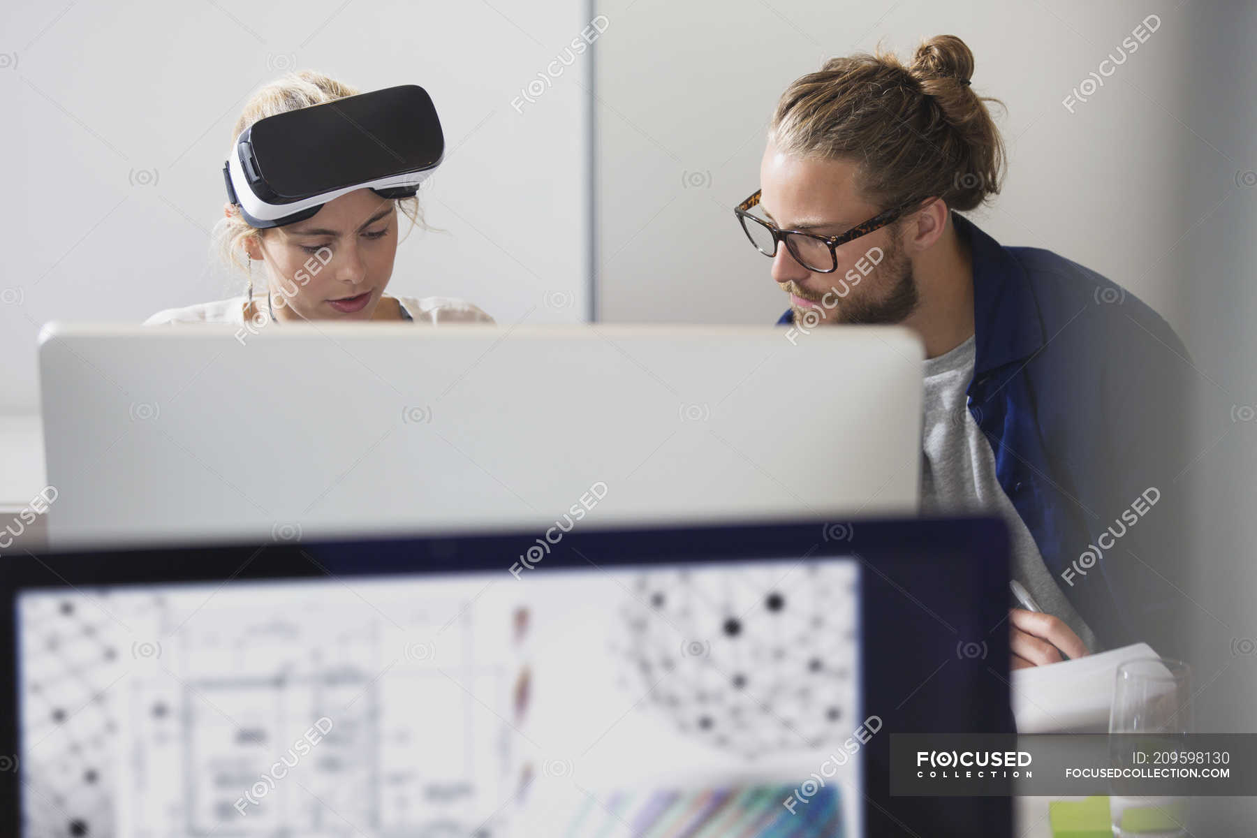 Focused computer programmers programming virtual reality simulator ...