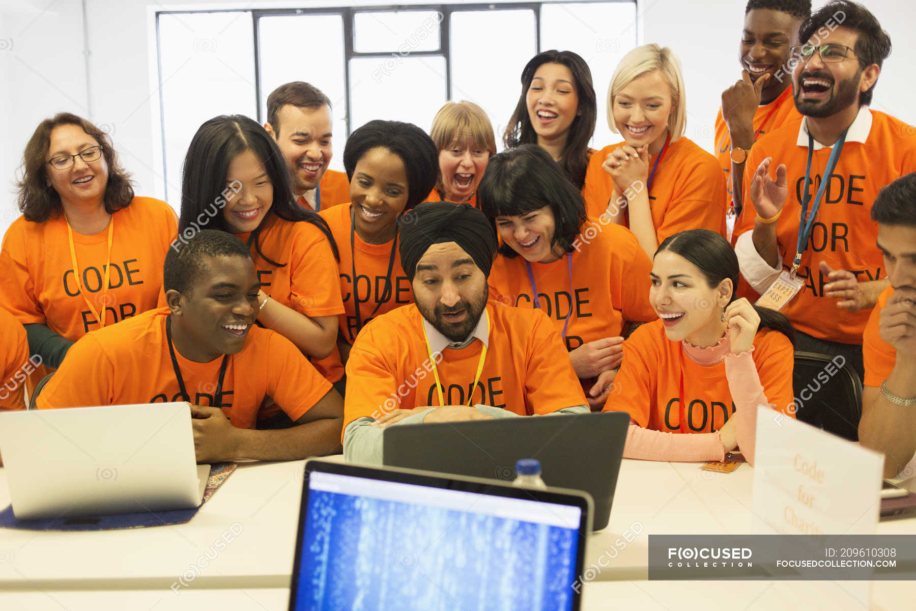 Happy hackers sharing laptop, coding for charity at hackathon ...