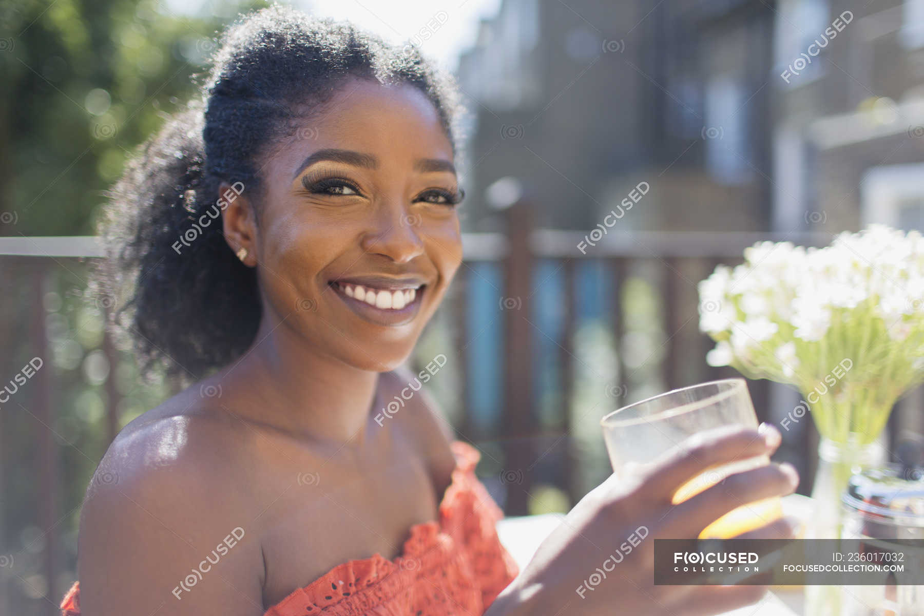 Portrait smiling, confident young woman drinking orange juice on sunny ... Portrait smiling, confident young woman drinking orange juice on sunny ...