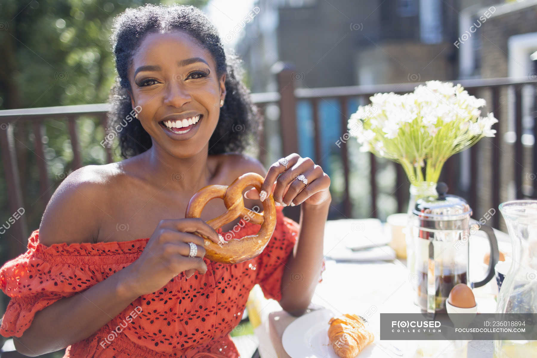 Portrait smiling, confident young woman with pretzel enjoying breakfast ... Portrait smiling, confident young woman with pretzel enjoying breakfast ...