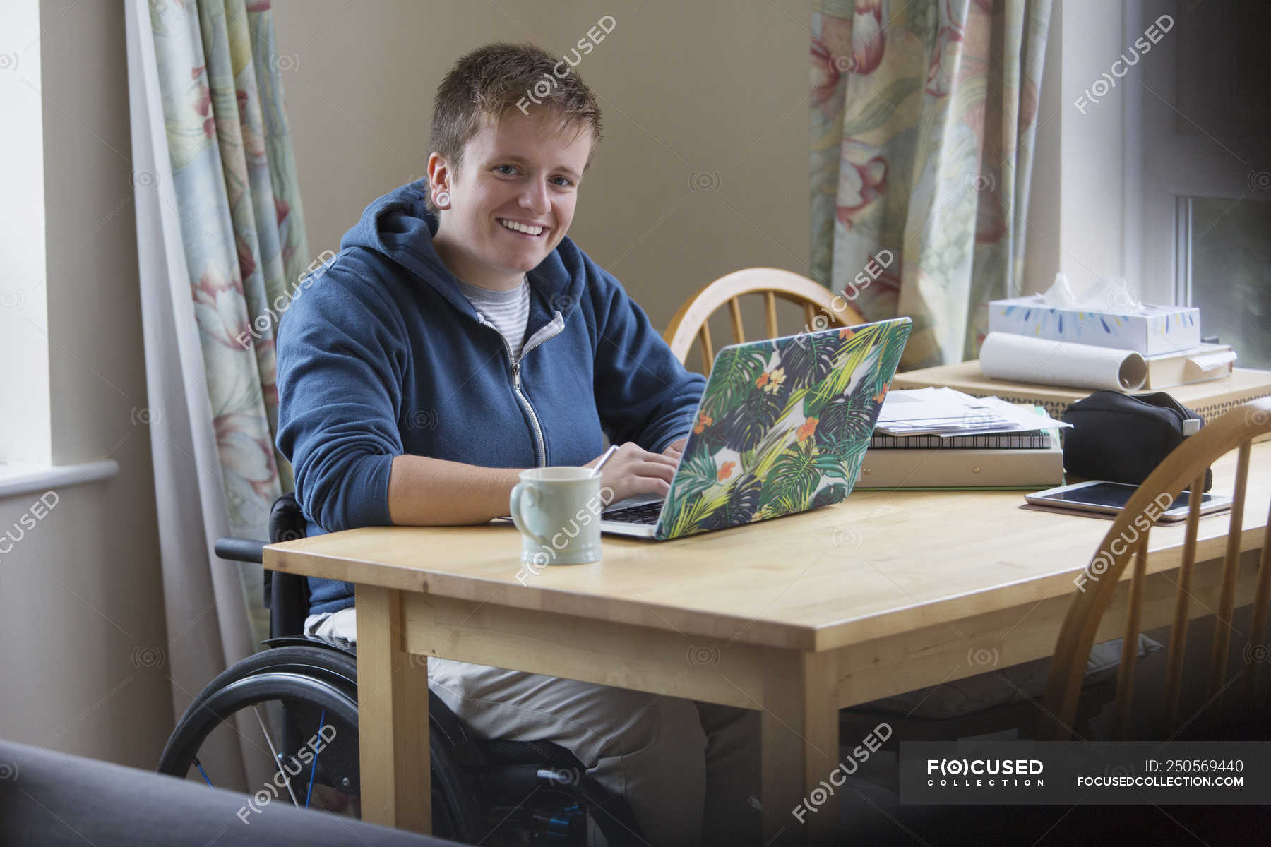 Portrait smiling, confident young woman in wheelchair using laptop at ... Portrait smiling, confident young woman in wheelchair using laptop at ...
