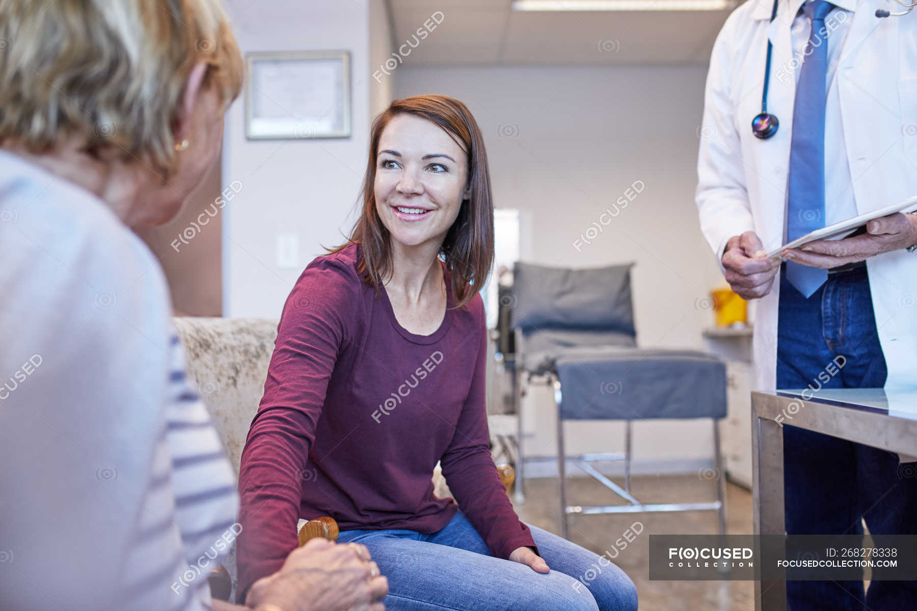Médico hablando con pacientes en consultorio médico — Descendientes ...