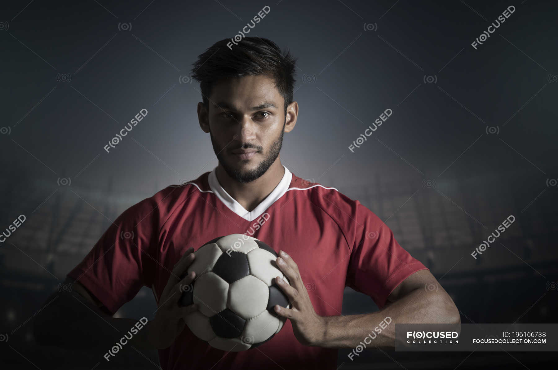 Football player holding football with both hands with stadium at ...