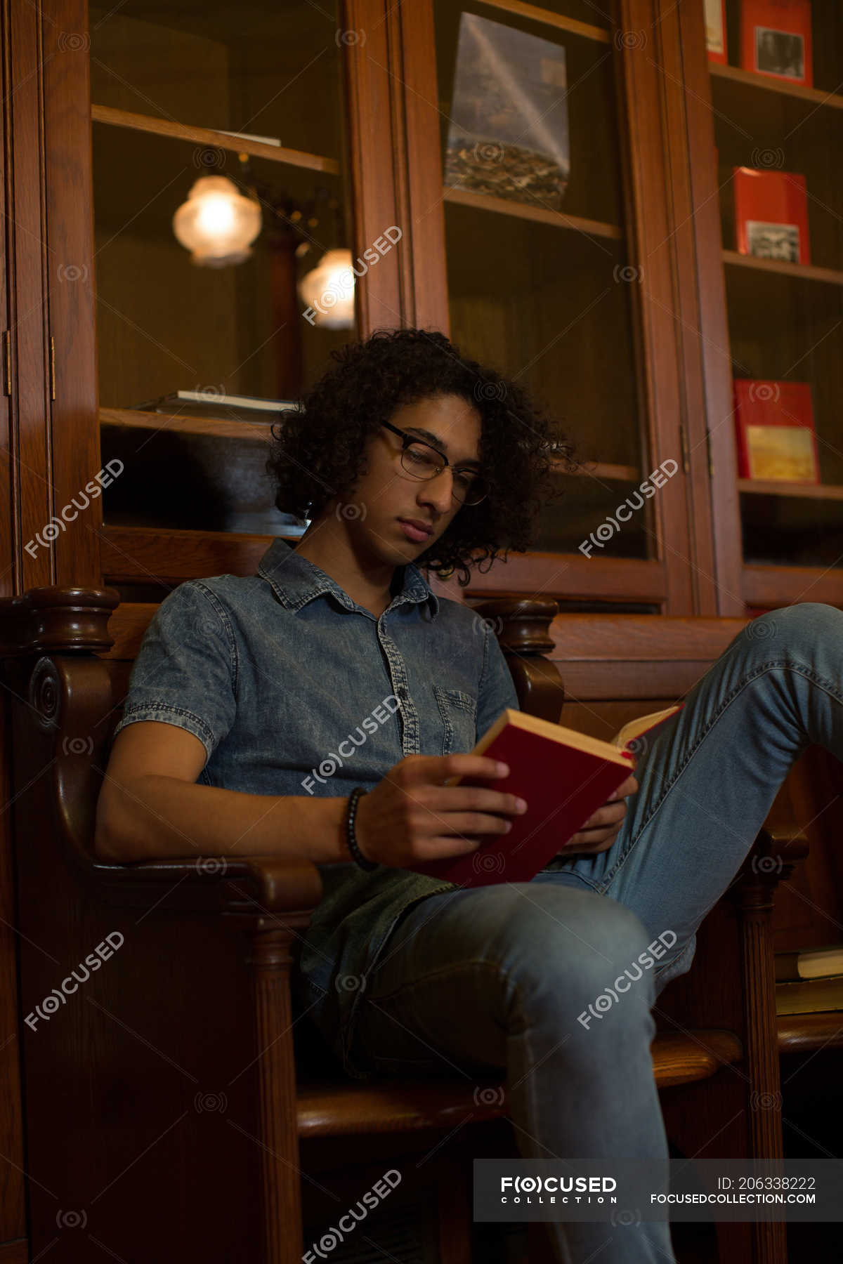 Young man reading a book in library — Bookshelf, study - Stock Photo ...