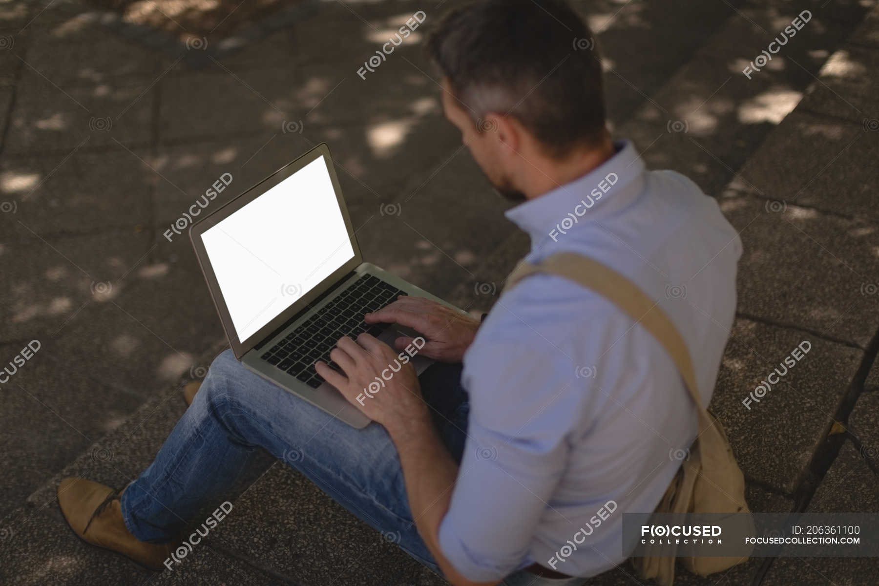 Rear view of man using laptop on steps — concentration, Wireless ...