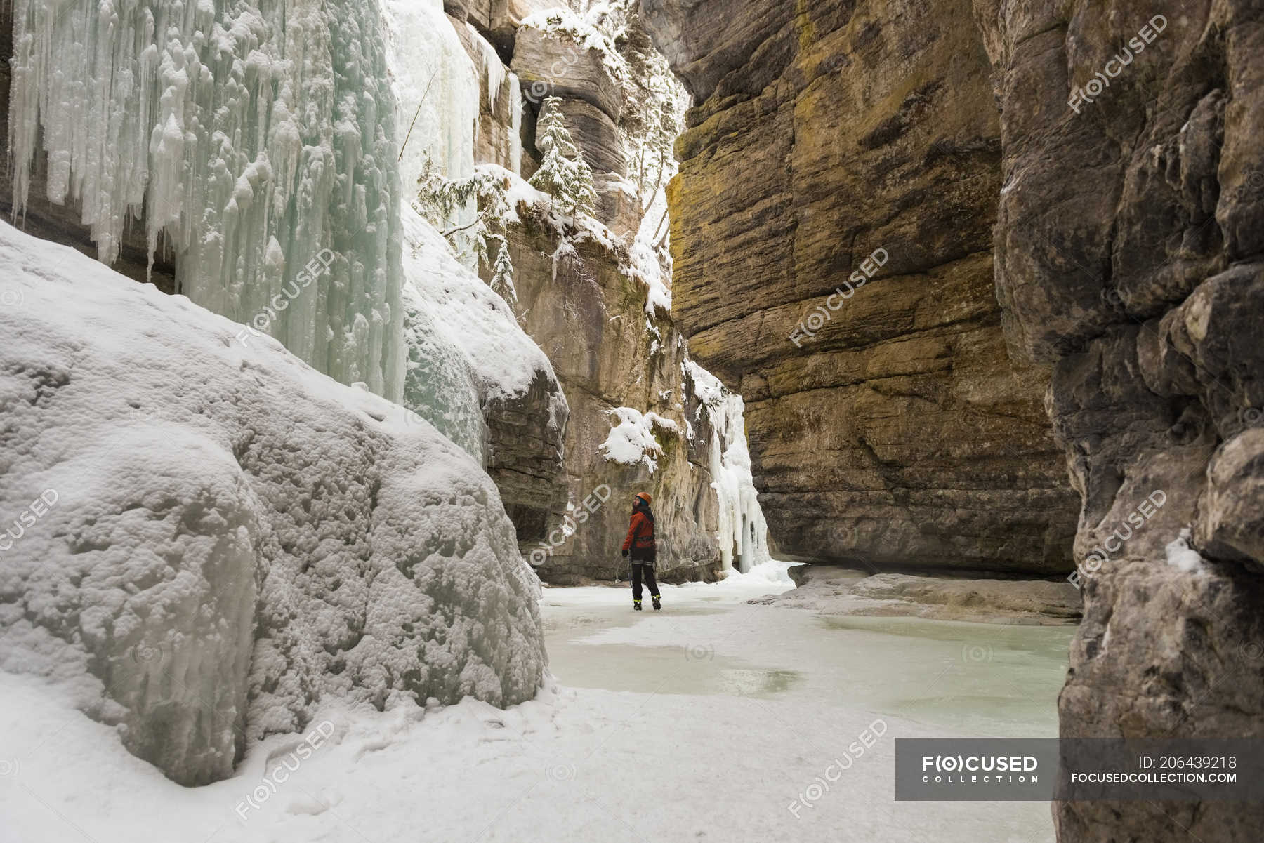 Female rock climber looking at rocky ice mountain during winter ...