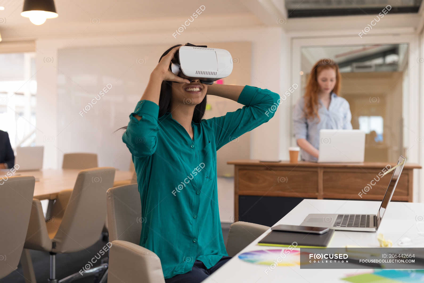 Female graphic designer using virtual reality headset in office ...