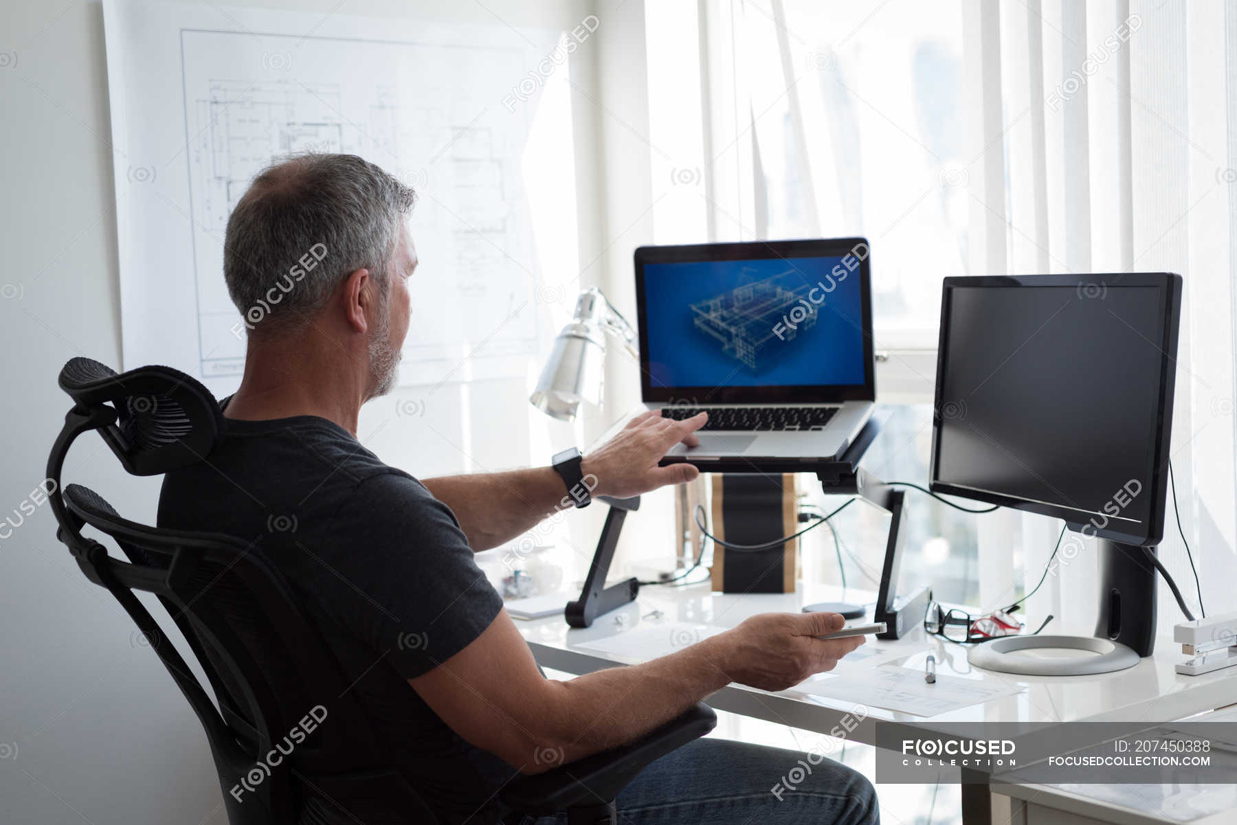 Man preparing architectural design on laptop and computer at home ...