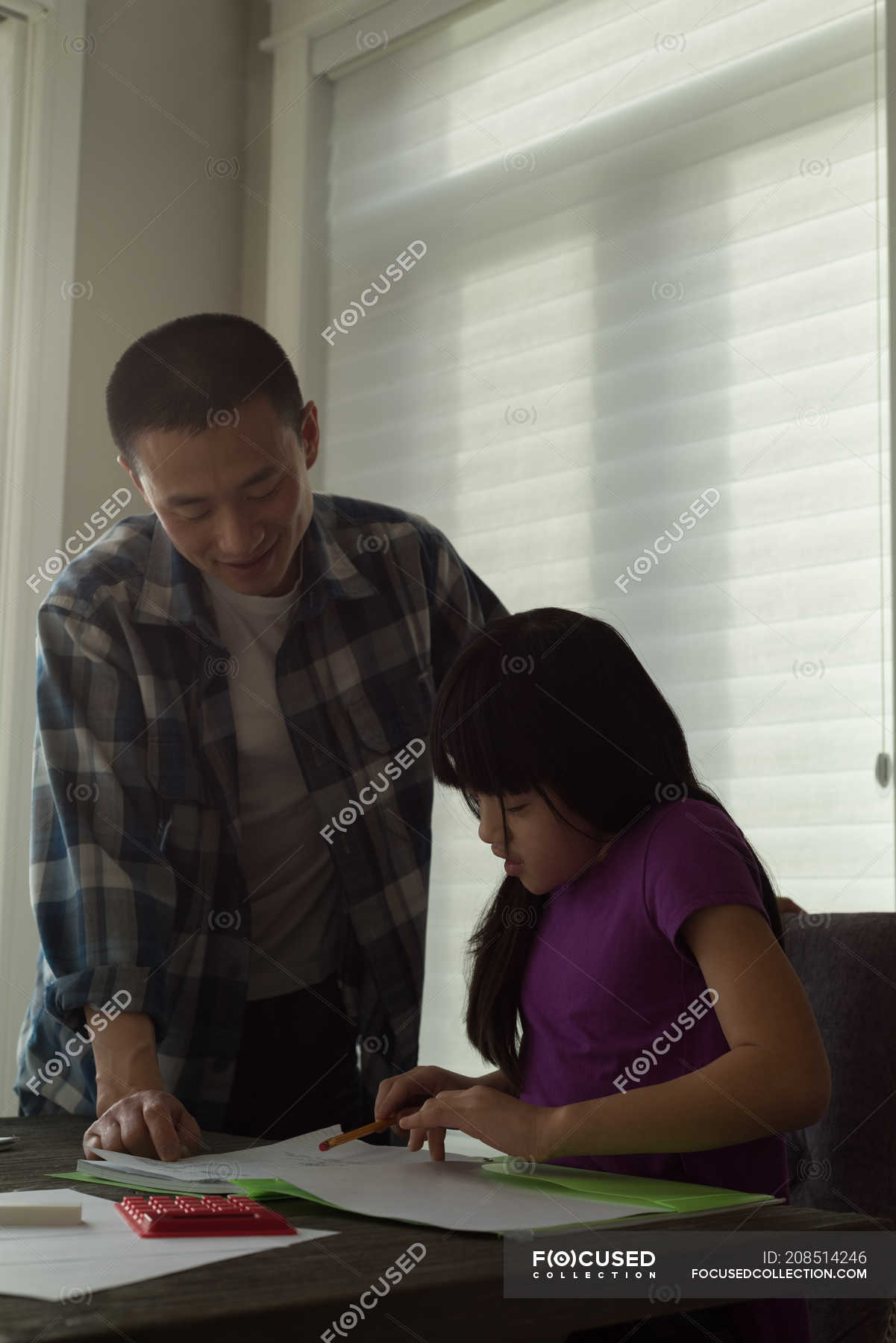 Father assisting her daughter in doing homework at home — asian, man - Stock Photo | #208514246