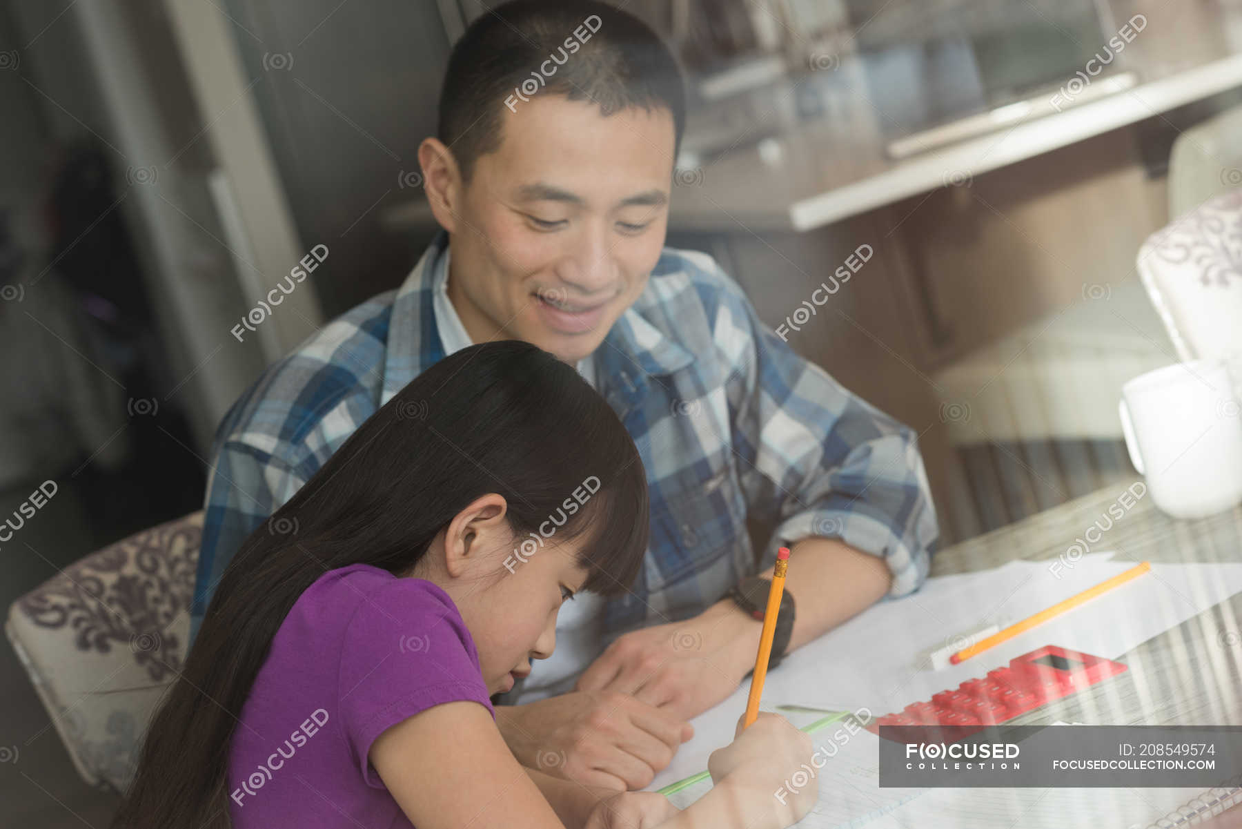 Father assisting her daughter in doing homework at home — 30s, modern - Stock Photo | #208549574