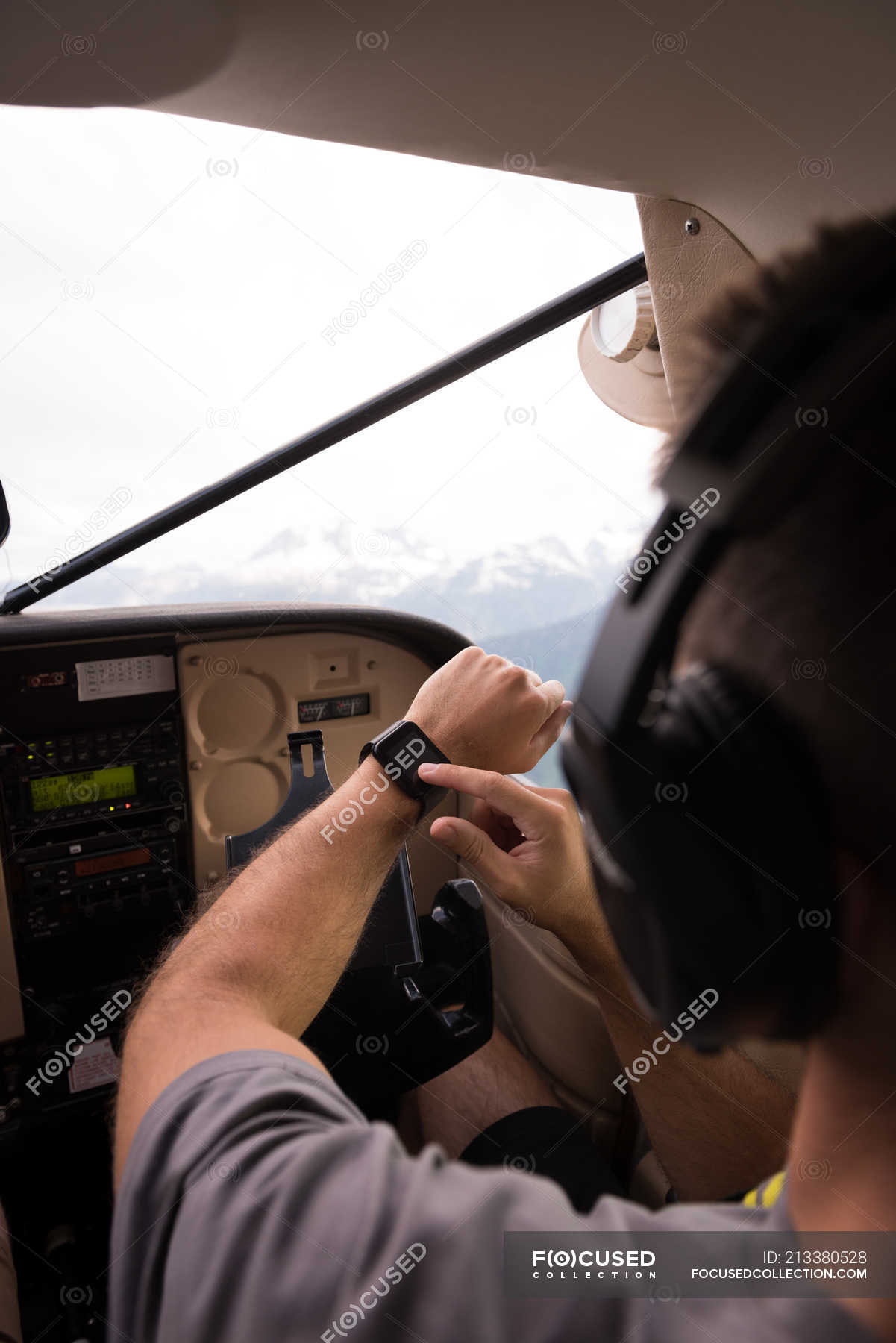 Pilot using smartwatch while flying in aircraft cockpit — interior ...