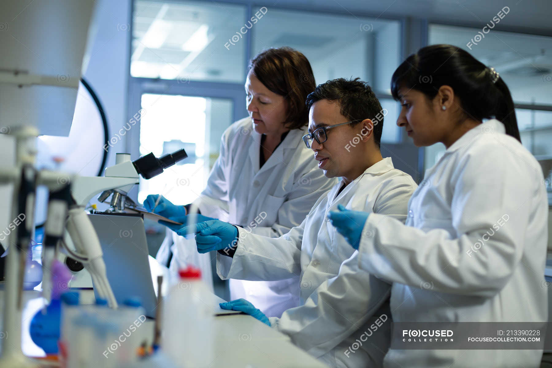 Team of scientists experimenting together in laboratory — solution ... Team of scientists experimenting together in laboratory — solution ...