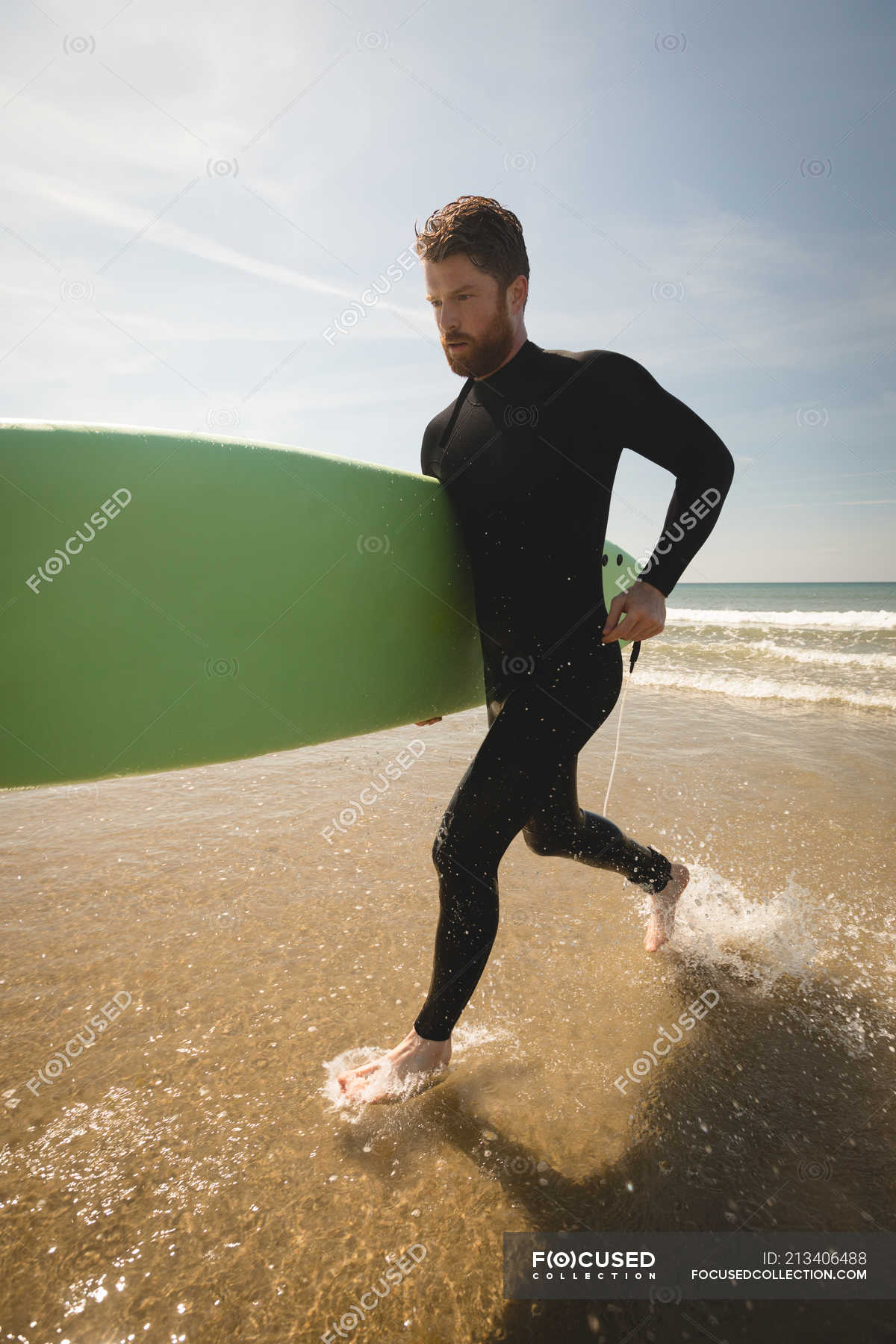 Surfer with surfboard running at beach on a sunny day — tranquility ...