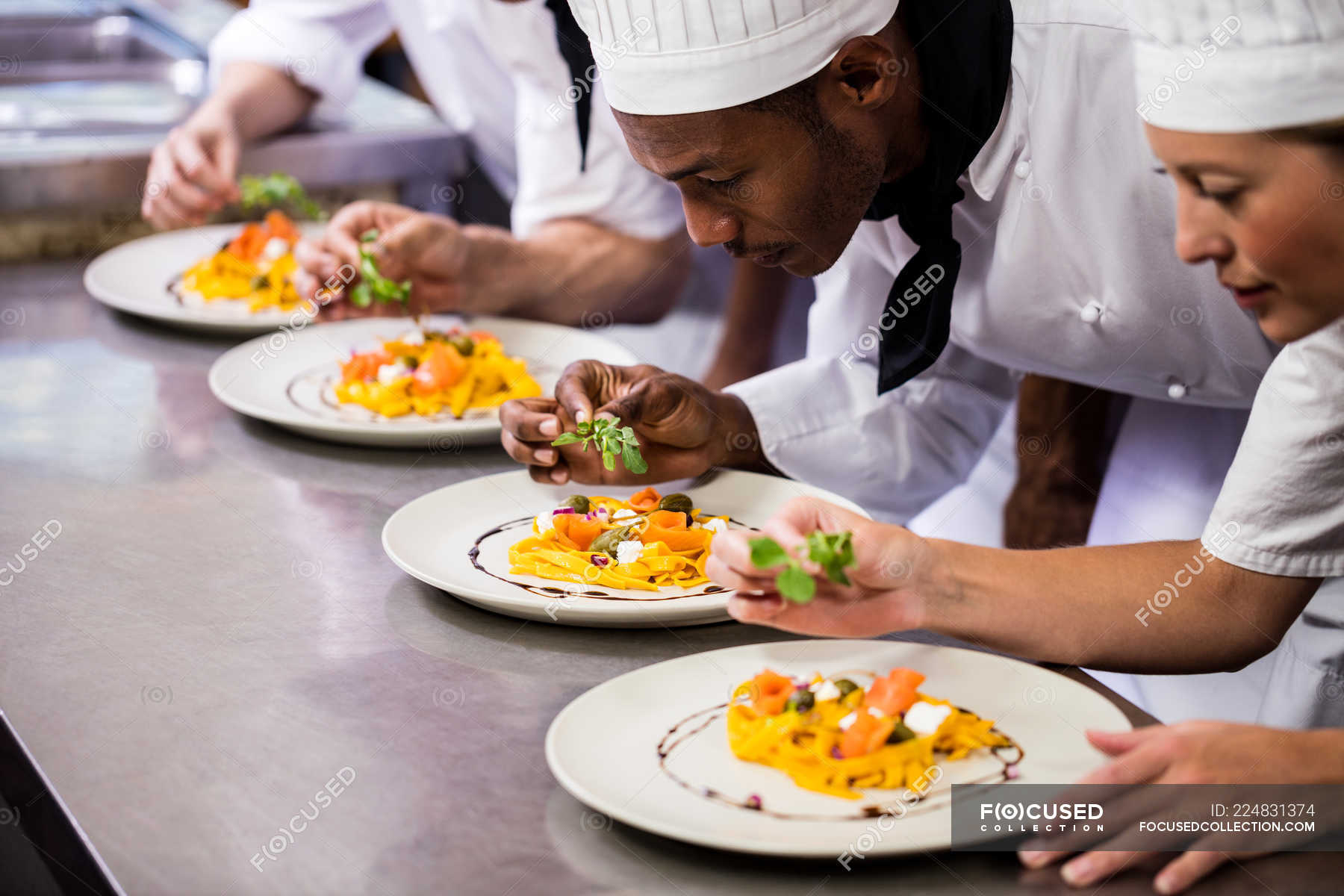 Group of chef garnishing food on plates — herb, commercial - Stock ...