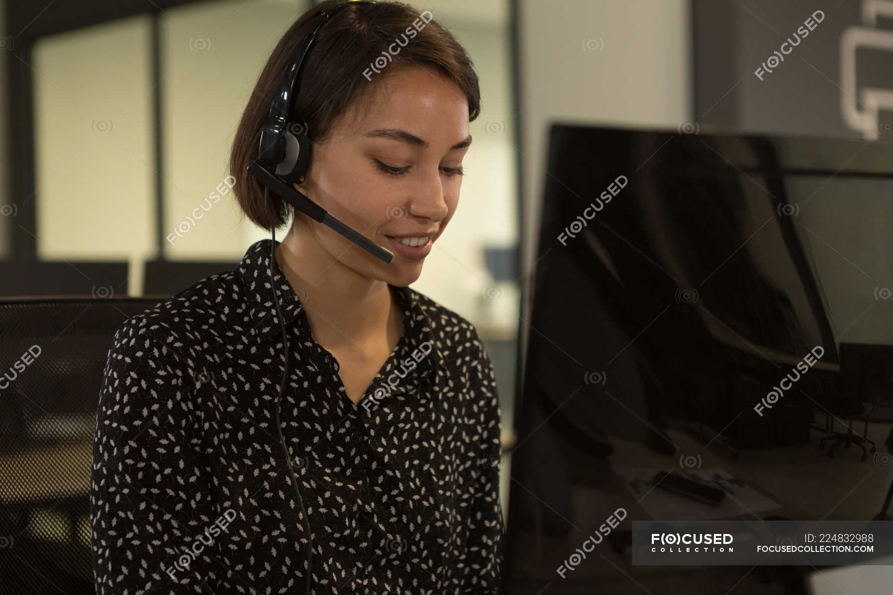 Customer service executive talking on headset at desk in office ...