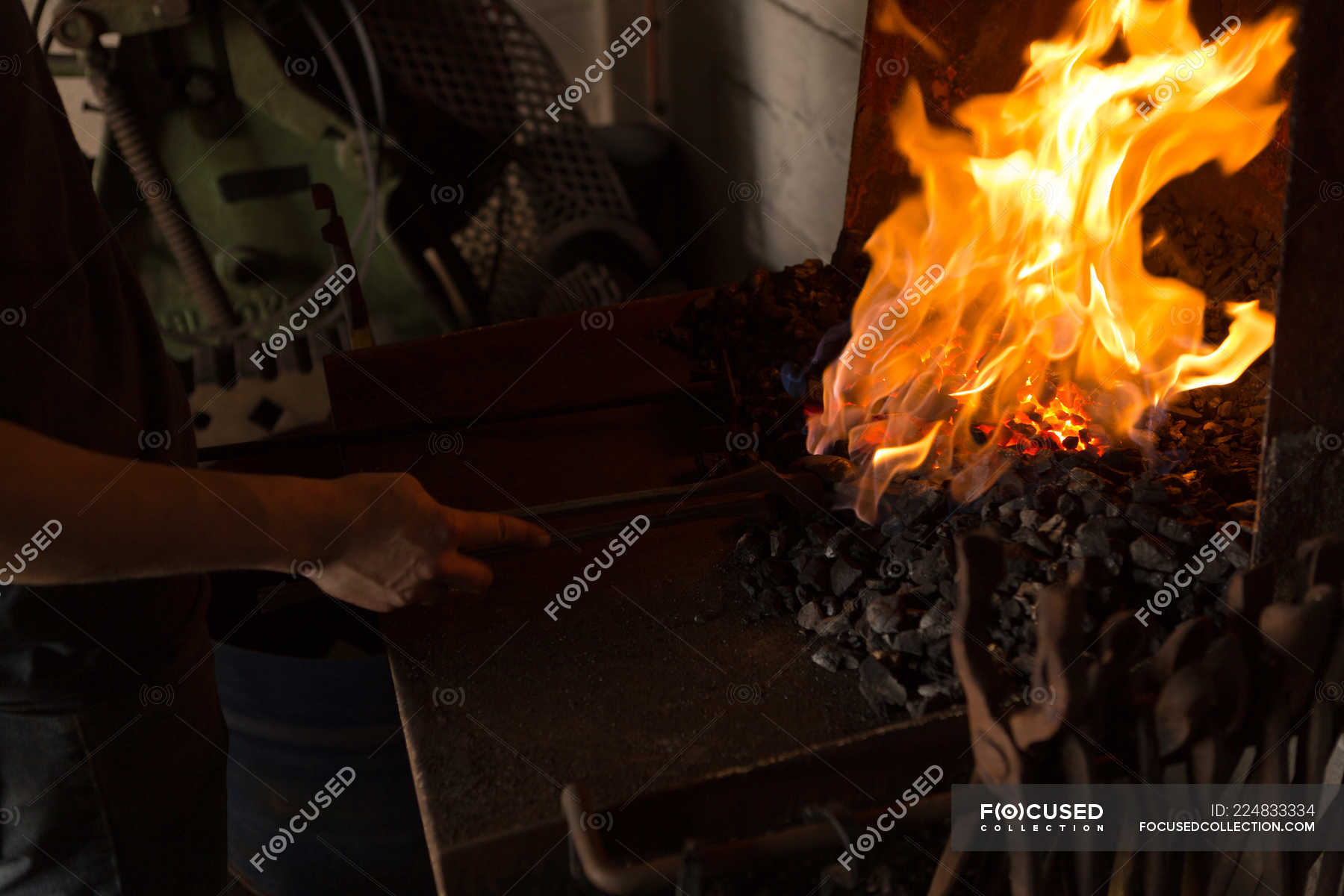 Mid Section Of Female Metalsmith Heating Horseshoe In Fire Workshop