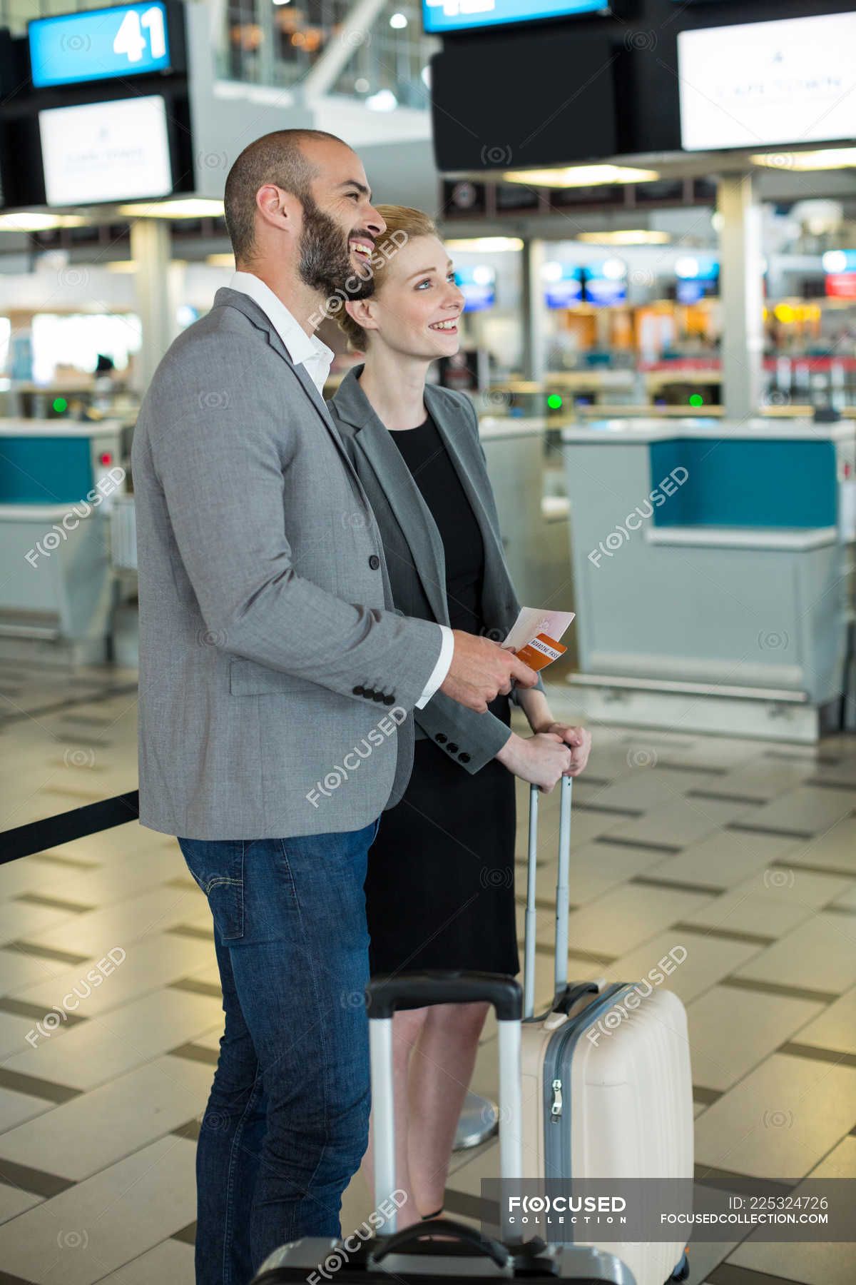 Business people waiting in queue at a check-in counter with luggage in airport terminal ...