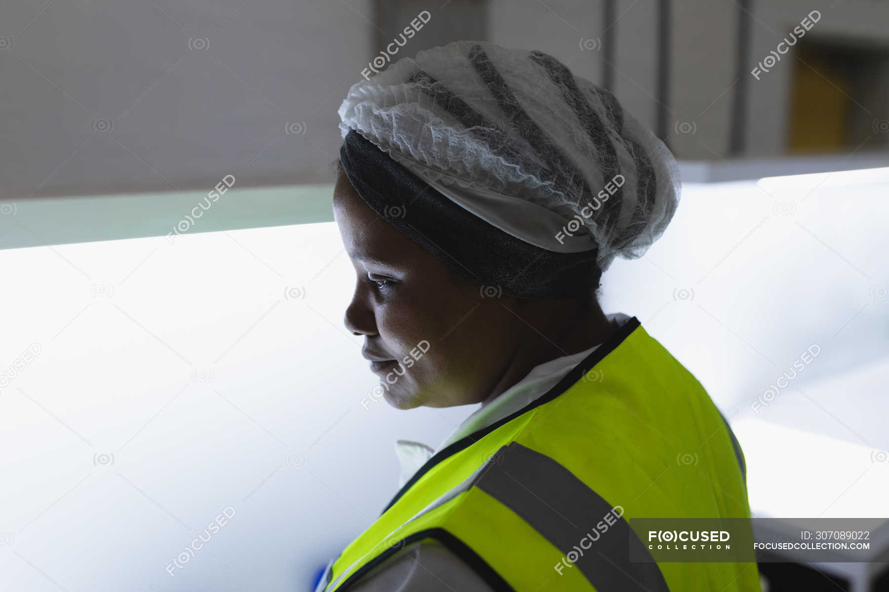 Side view close up of a young African American female factory worker ...