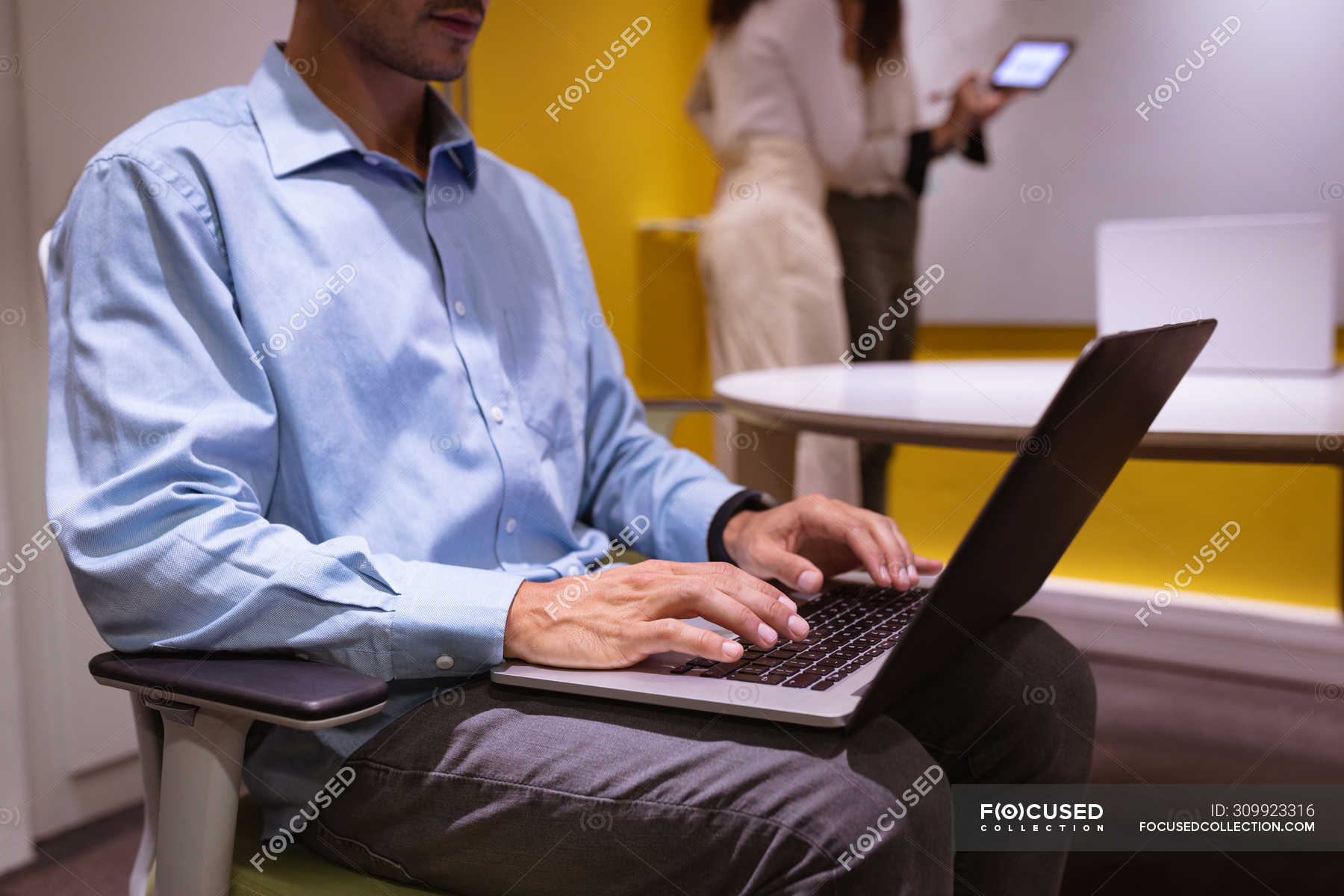 Side view mid section of a young Caucasian man sitting using a laptop ...