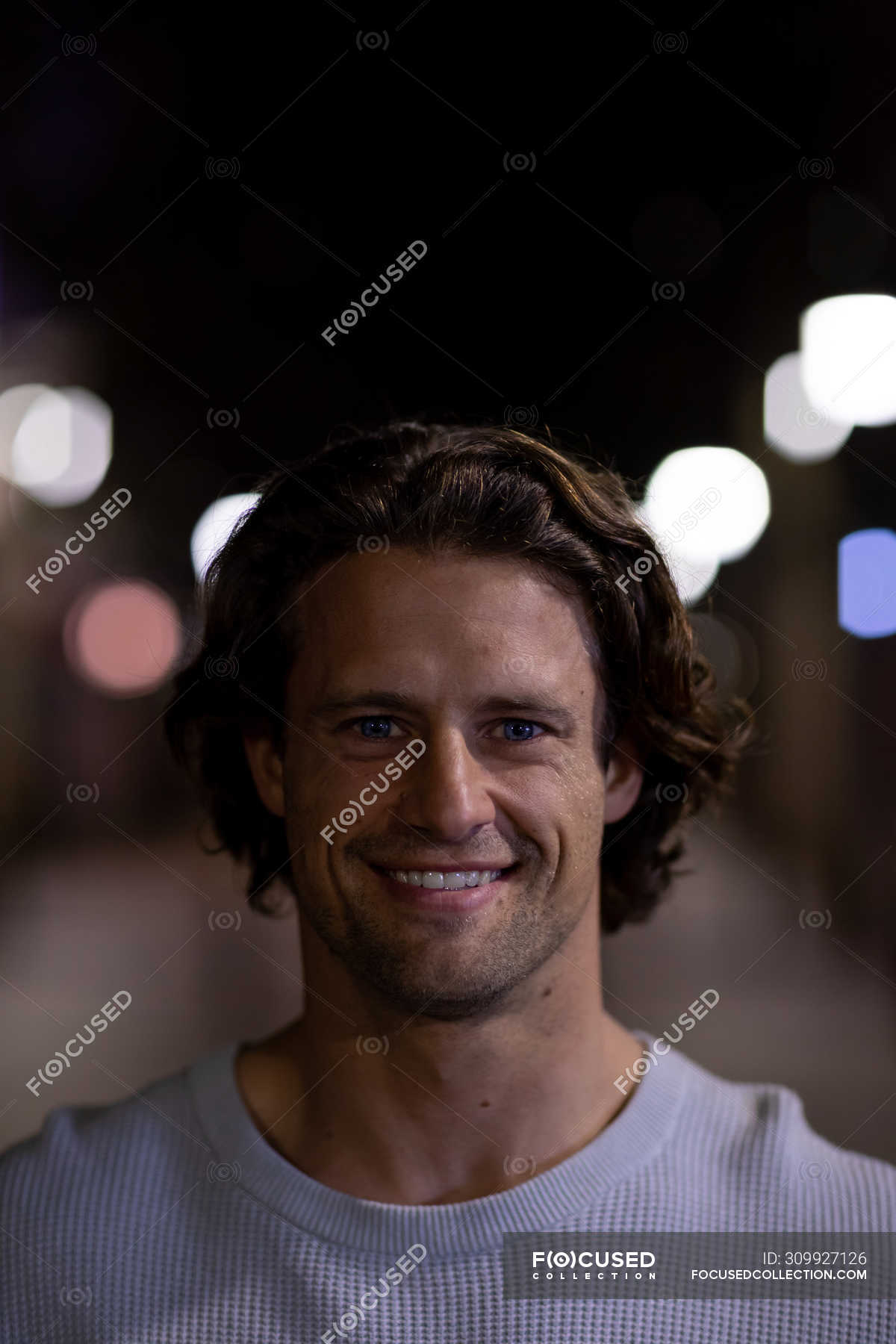Portrait close up of a young Caucasian man in the street smiling to ...