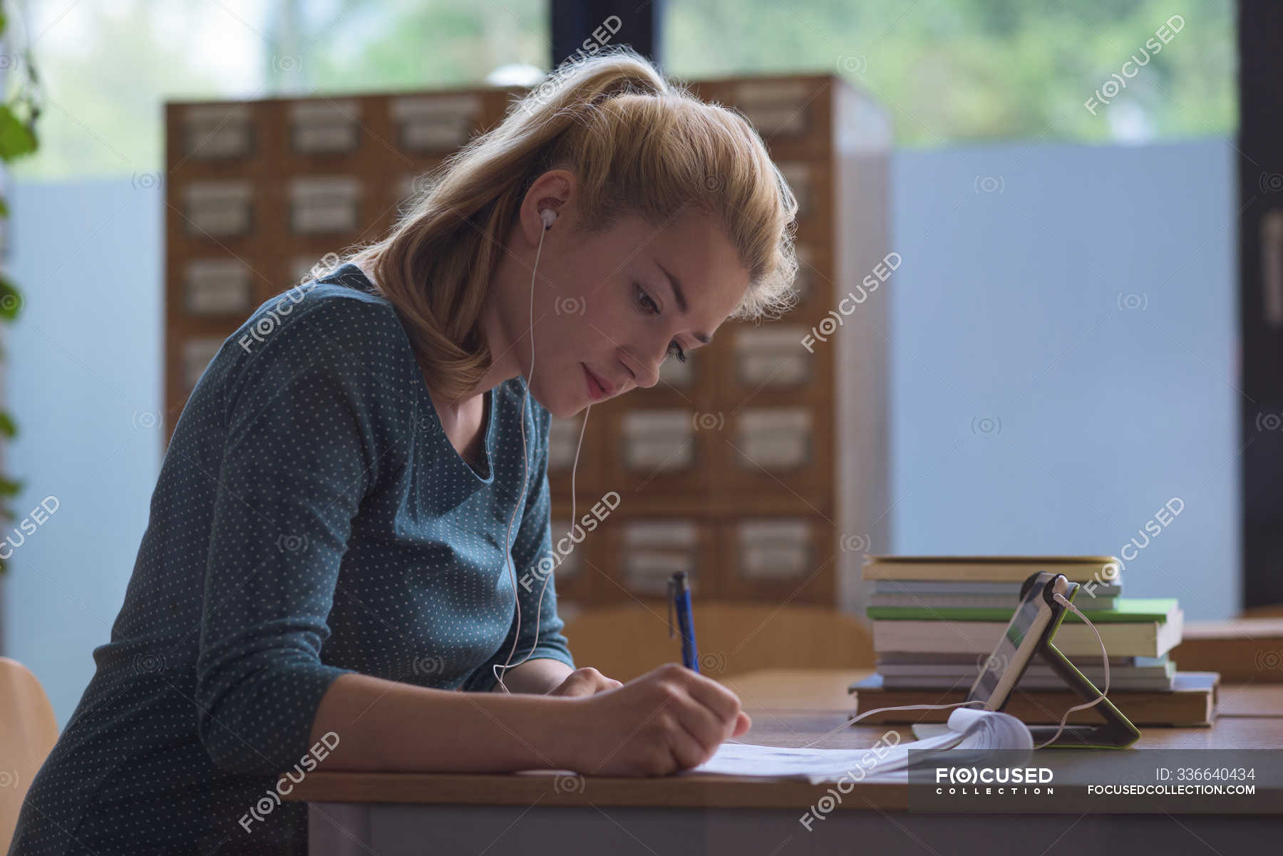 University student completing assignment in class at college — chair ...