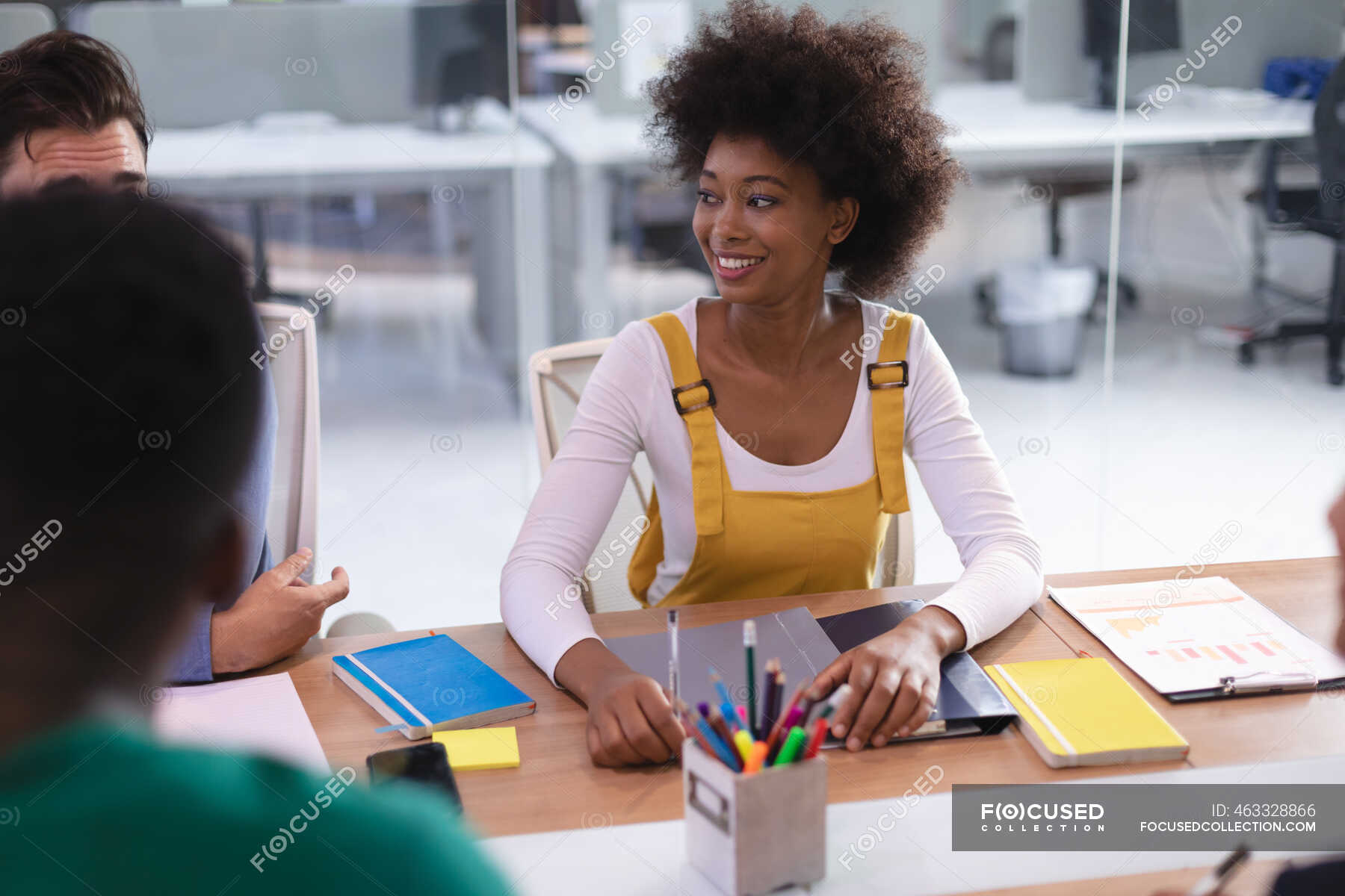 Feliz mujer de negocios afroamericana sentada en el escritorio en la sala de reuniones ...