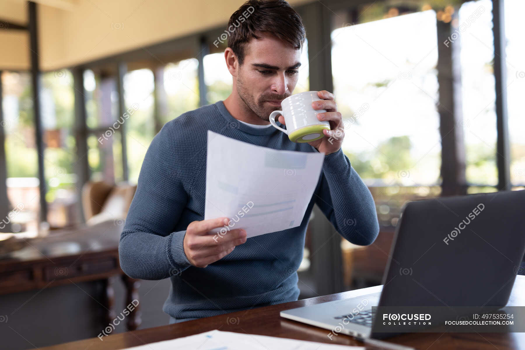 Caucasian man sitting at table and working remotely using laptop ...