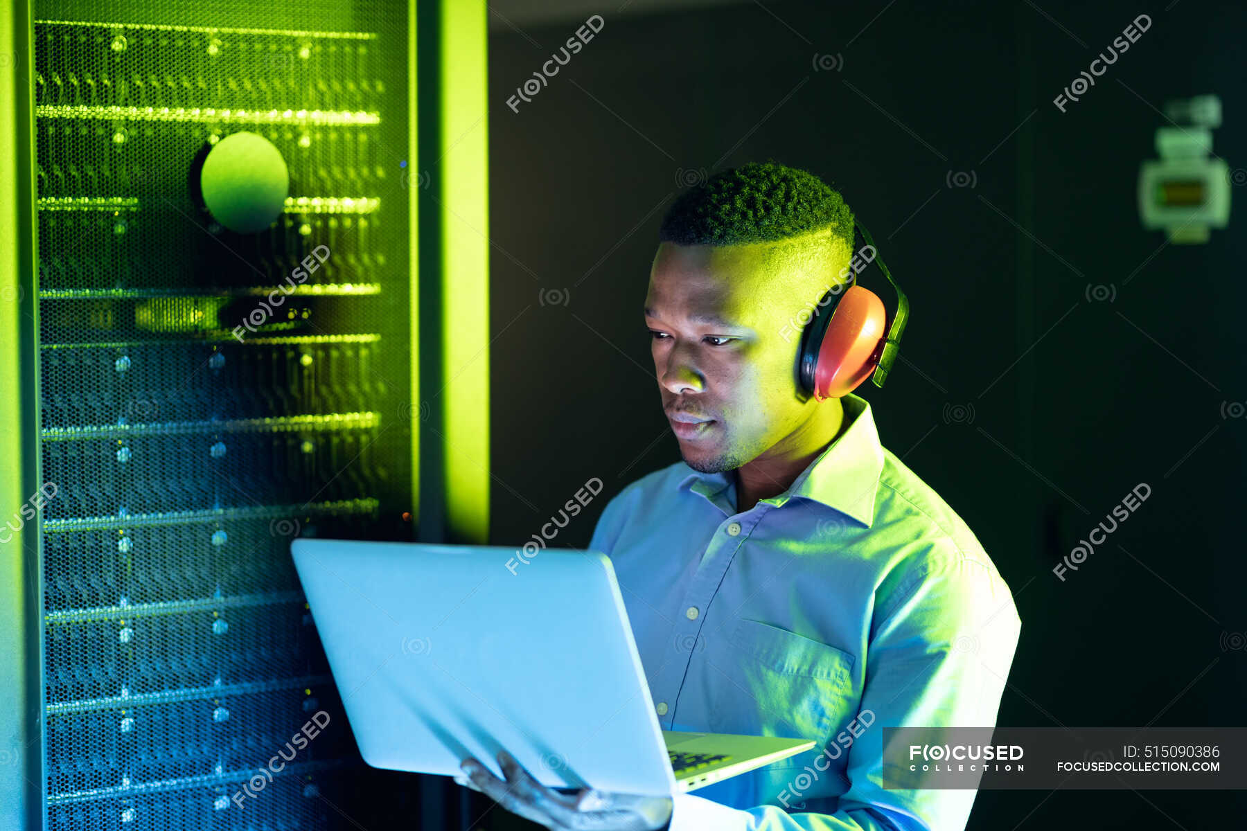 African american male computer technician wearing headphones using ...