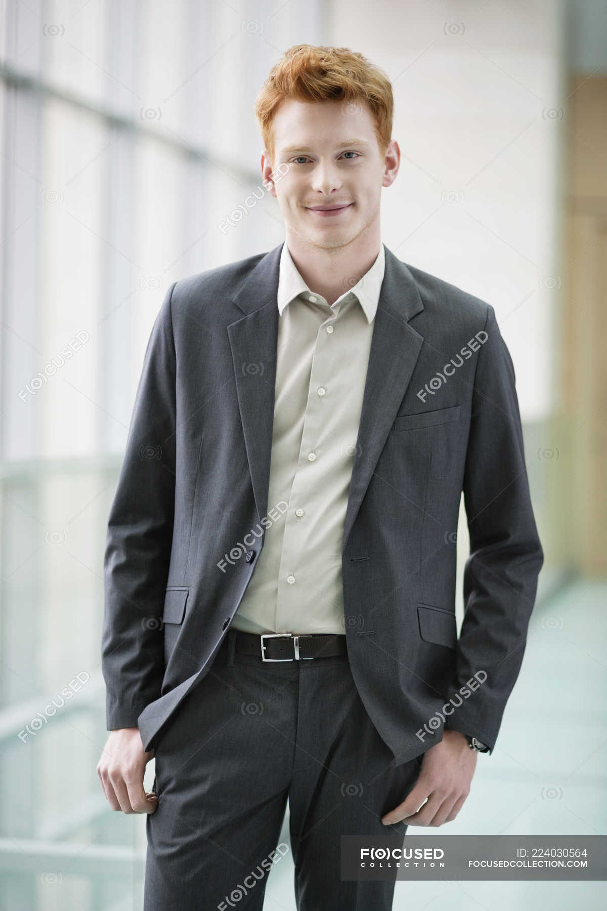 Portrait of smiling young businessman standing on blurred background ...