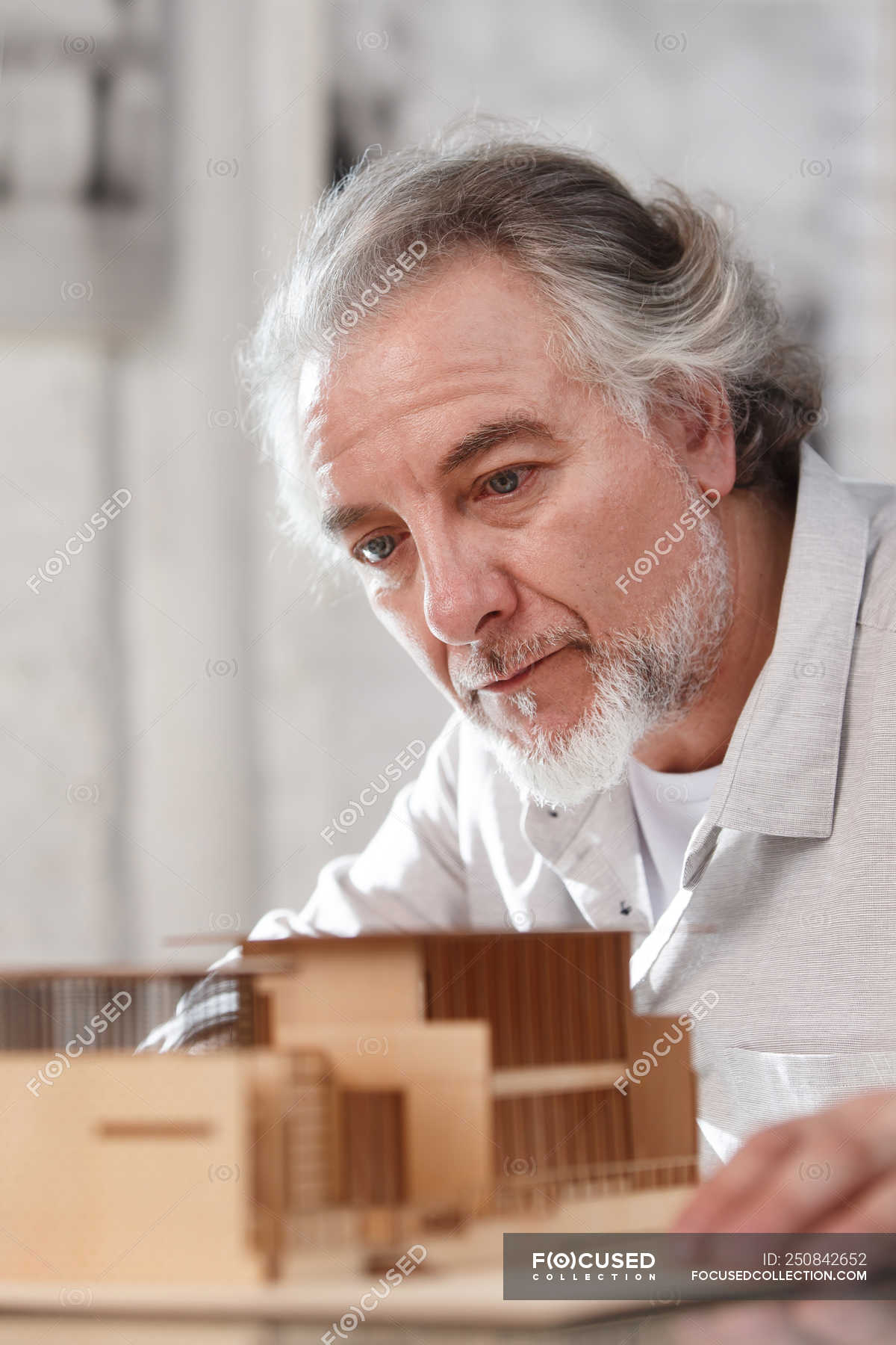 Professional concentrated mature architect working with building model ...
