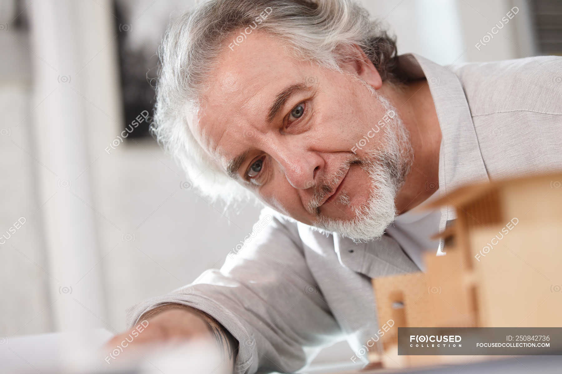 Professional mature architect working with building model at workplace ...